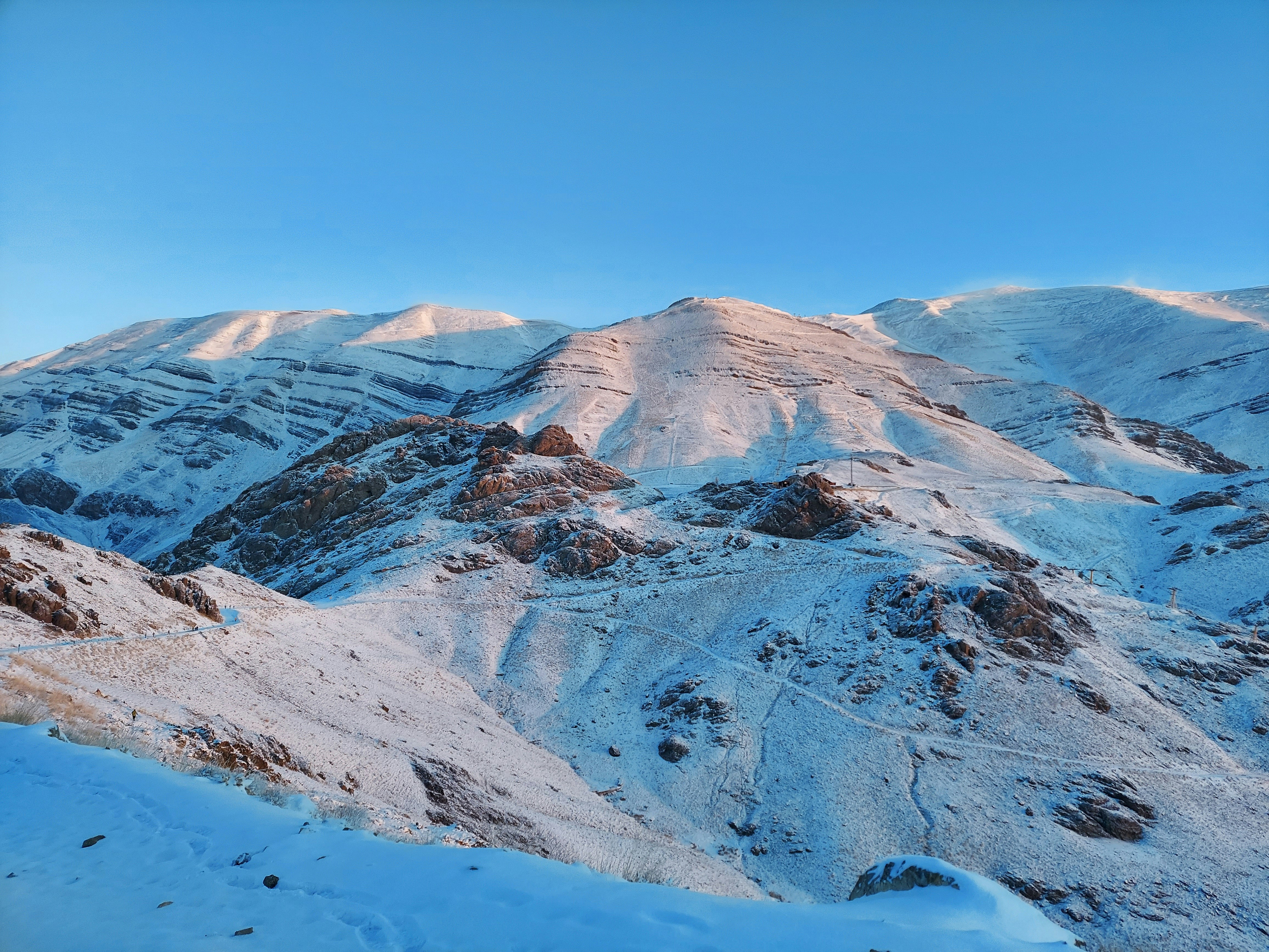 Snow-covered mountain landscape under a clear blue sky, showcasing the serene beauty of nature's winter palette.