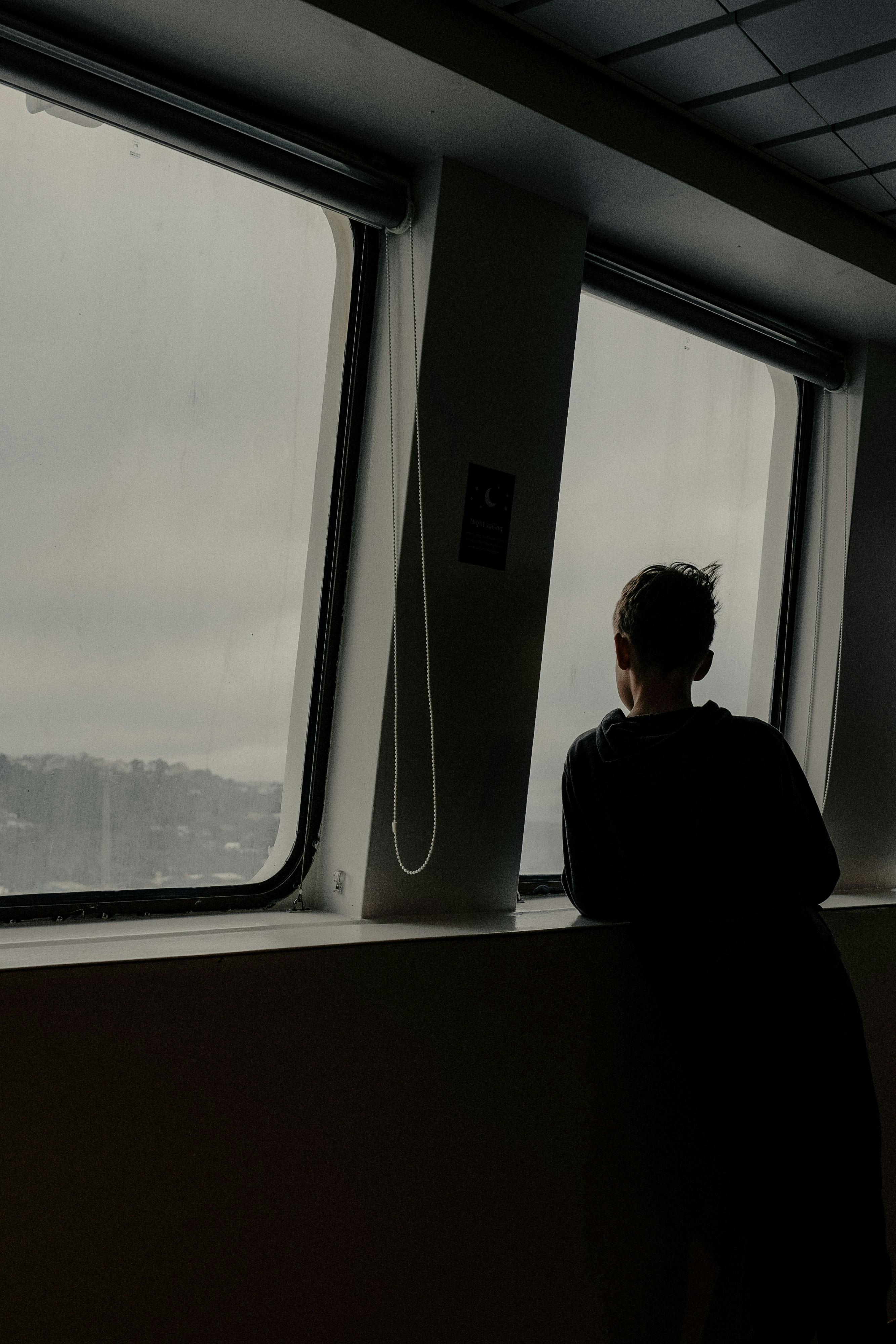 A person looking out of a window at a body of water photo – Free ...