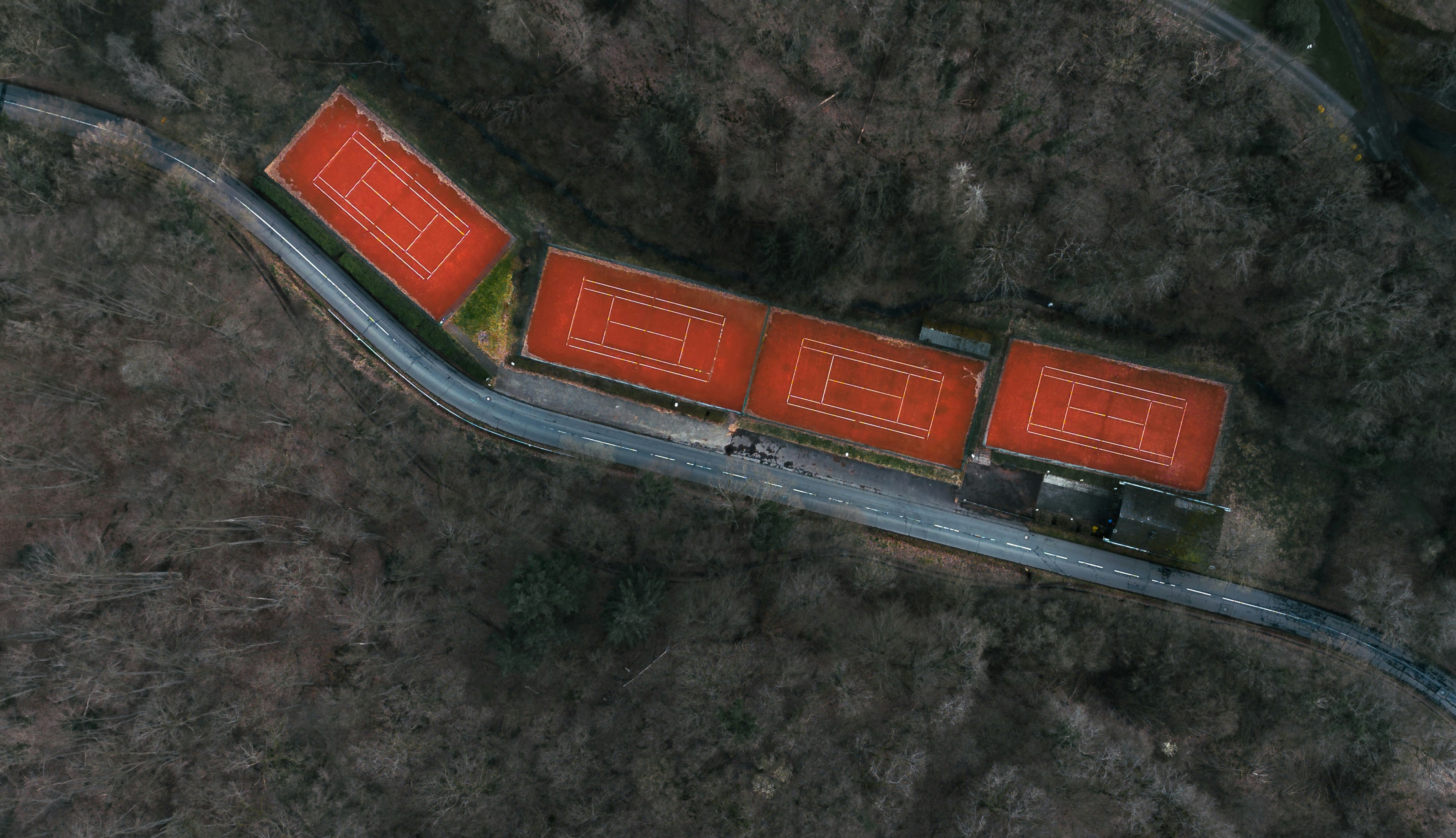 Quartet of Red Clay Courts Curl Along a Mountain Road