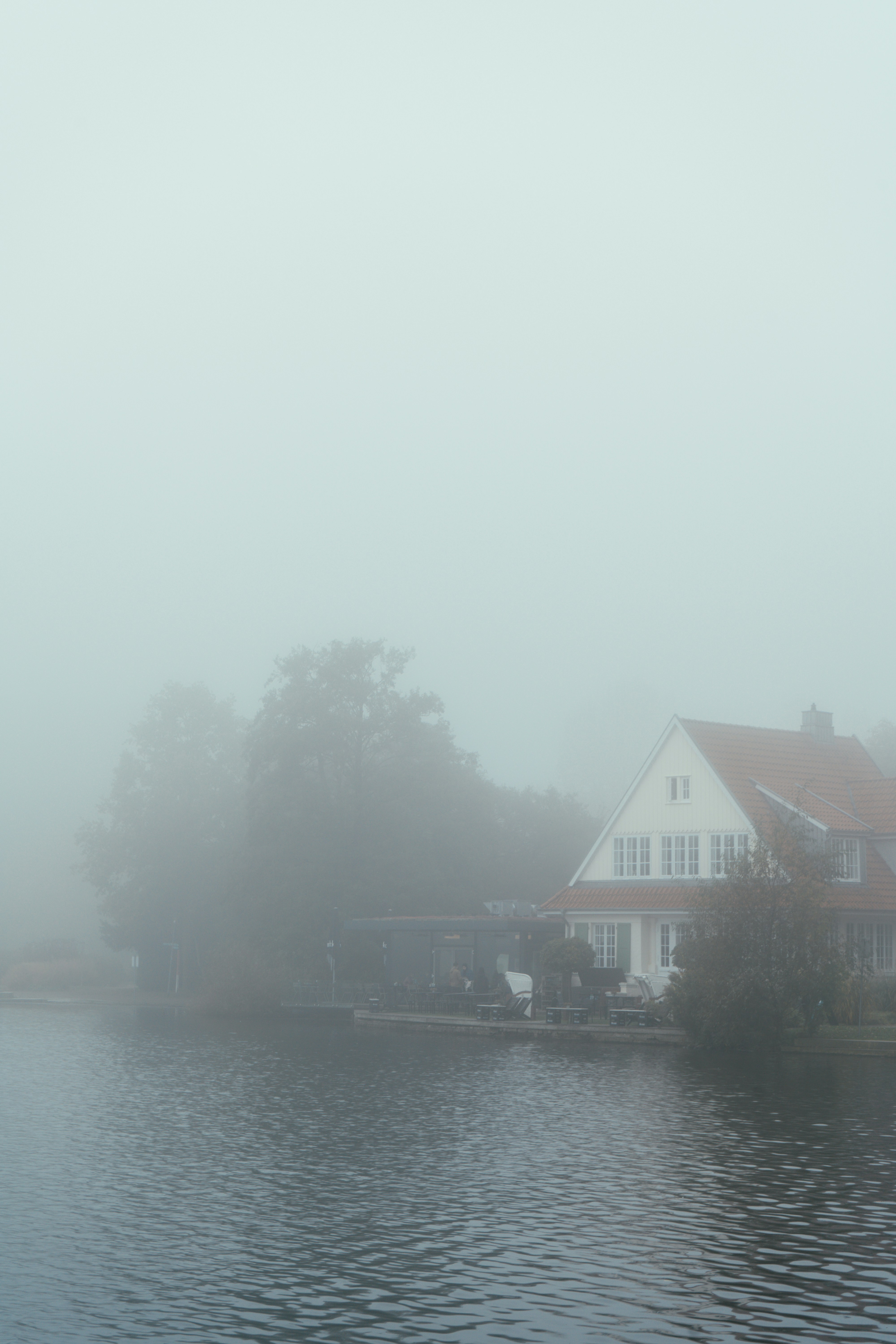 Mist Cloak: A Red-Roofed Lakeside Home Emerges Through Fog