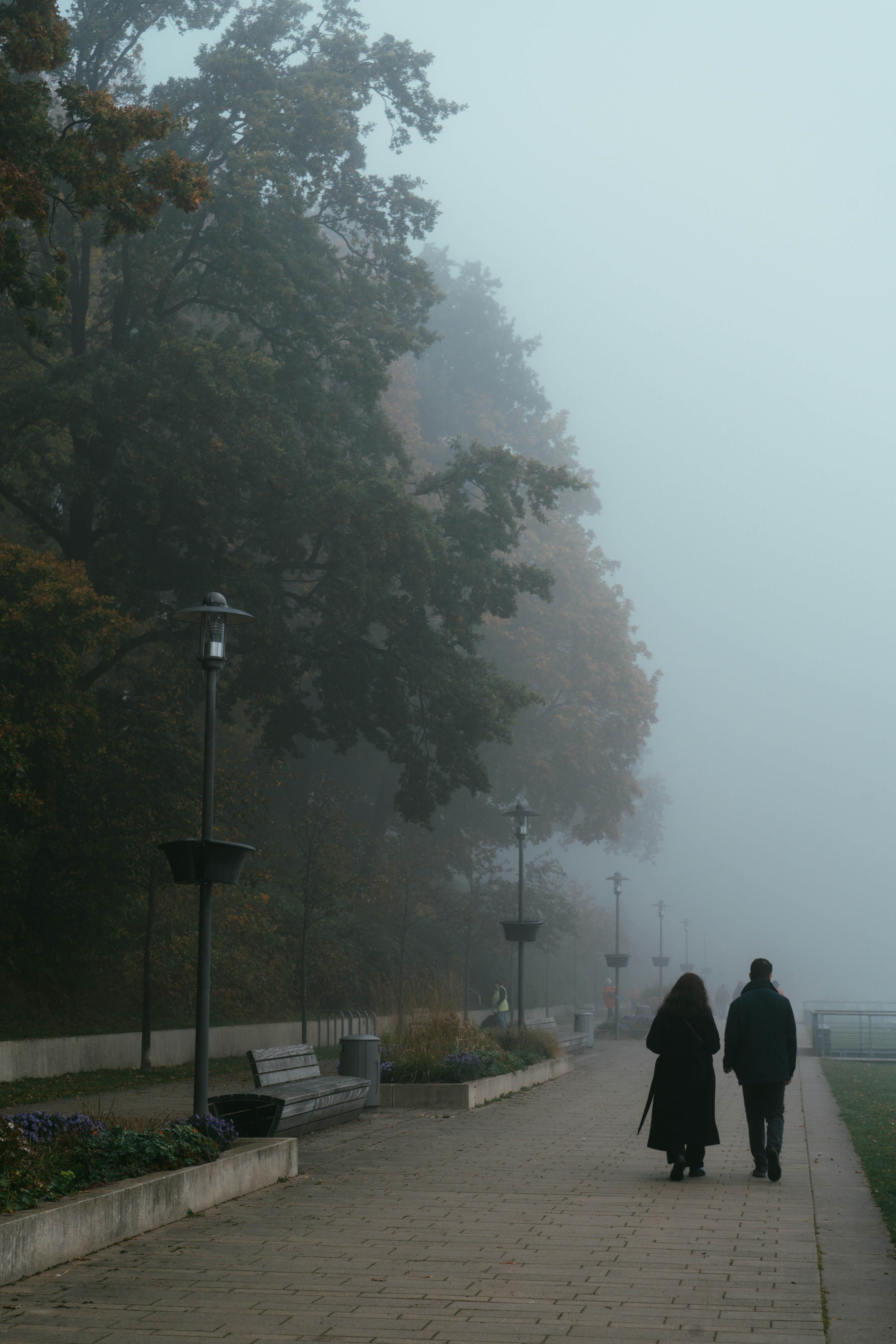 Mist-Wrapped Promenade: Two Figures Walking into the Fog