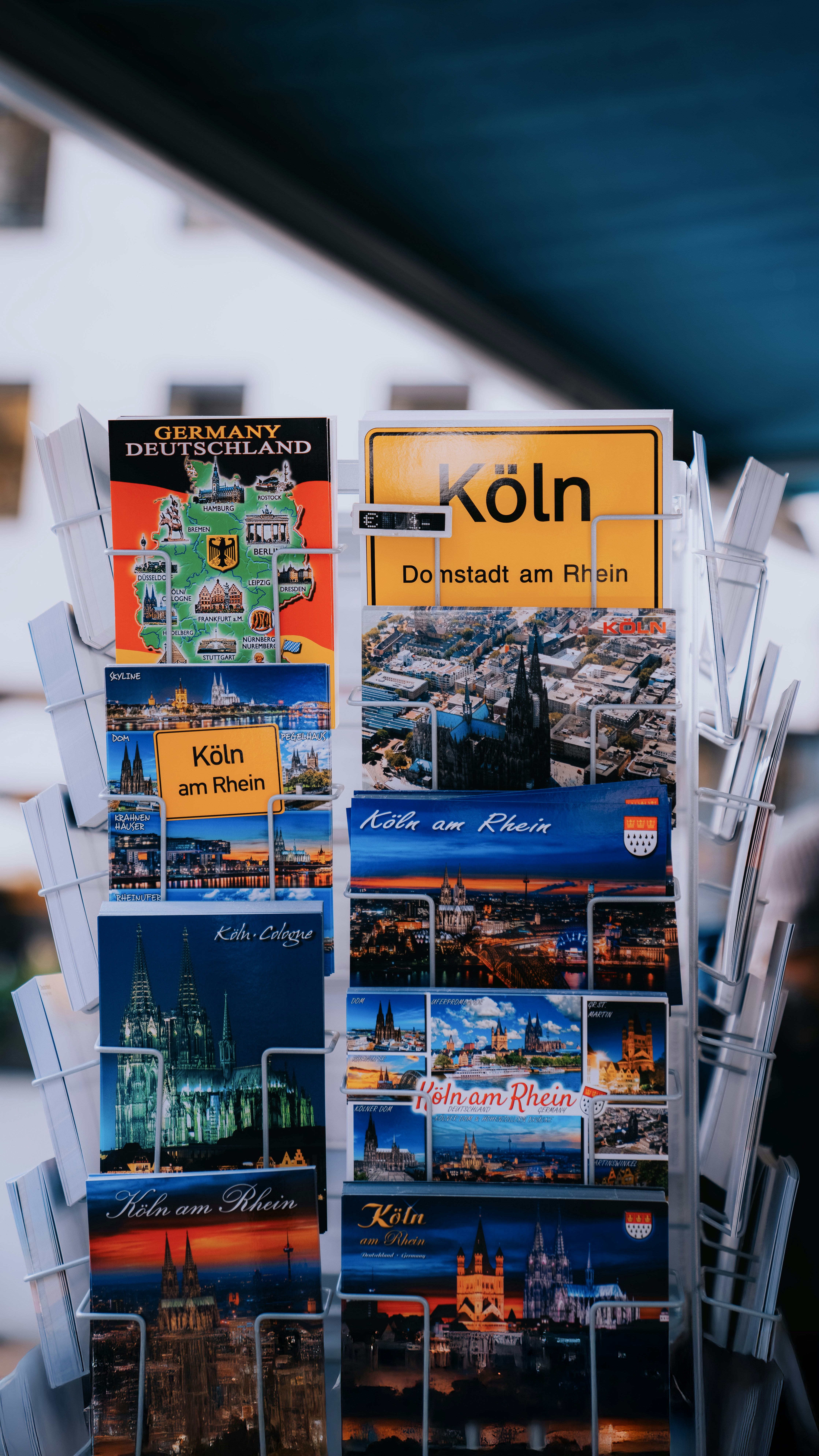 Display of Köln and Köln am Rhein postcards on a rack, forming a colorful collage of city landmarks.