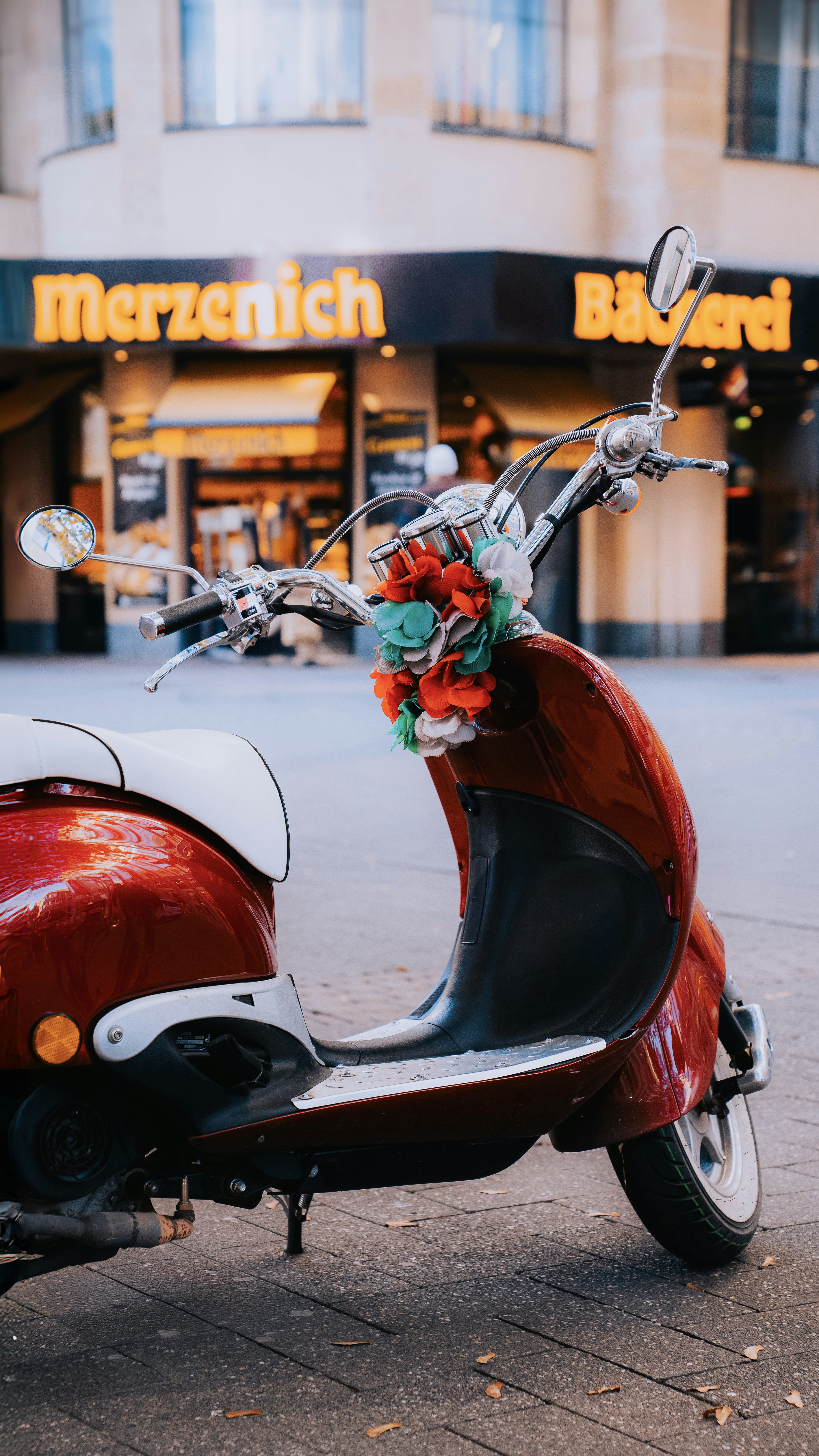 Floral Crest on a Red Vespa Framing a Cozy Bakery Facade