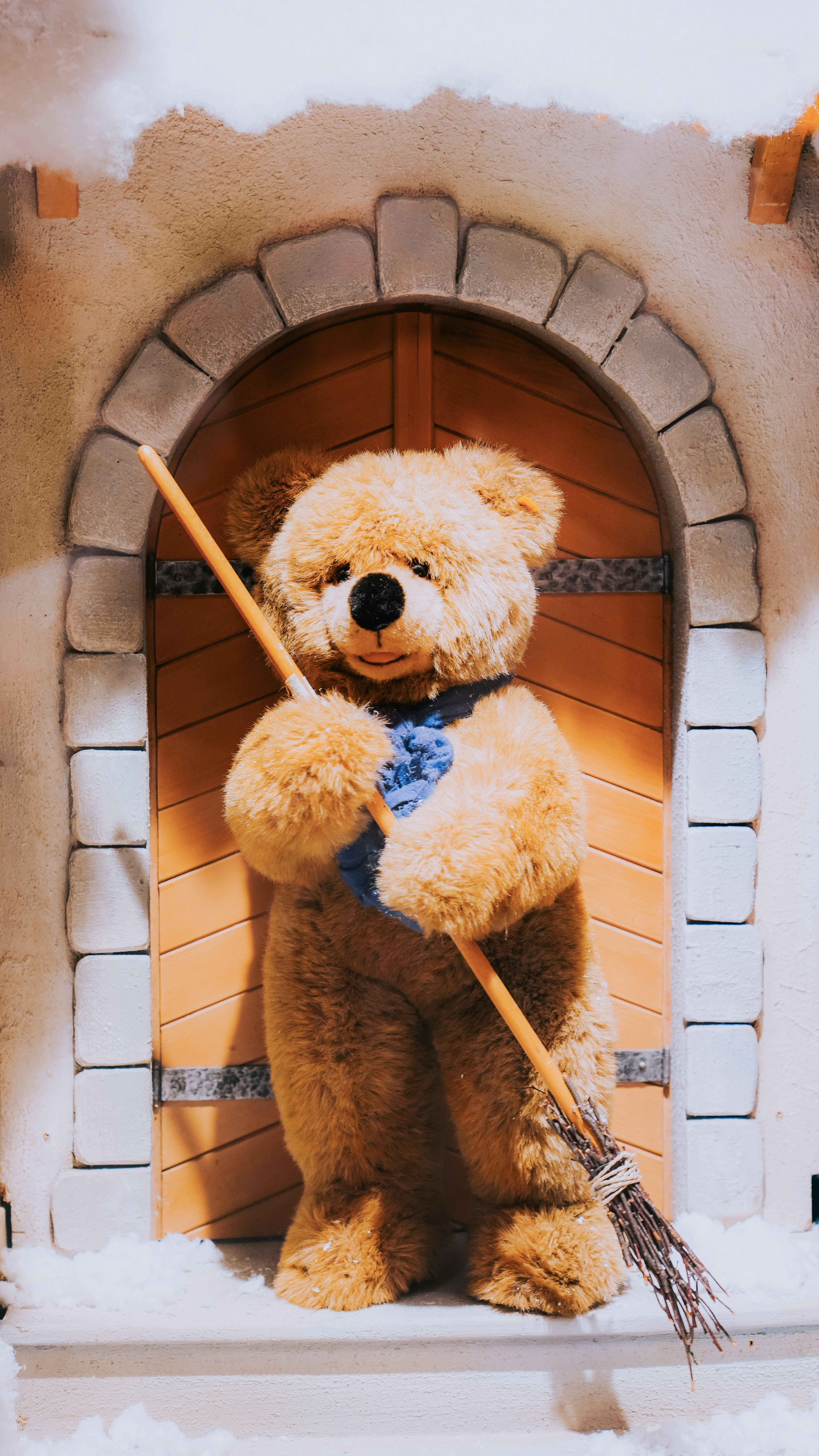 A teddy bear holding a broom in front of a brick oven photo – Free ...