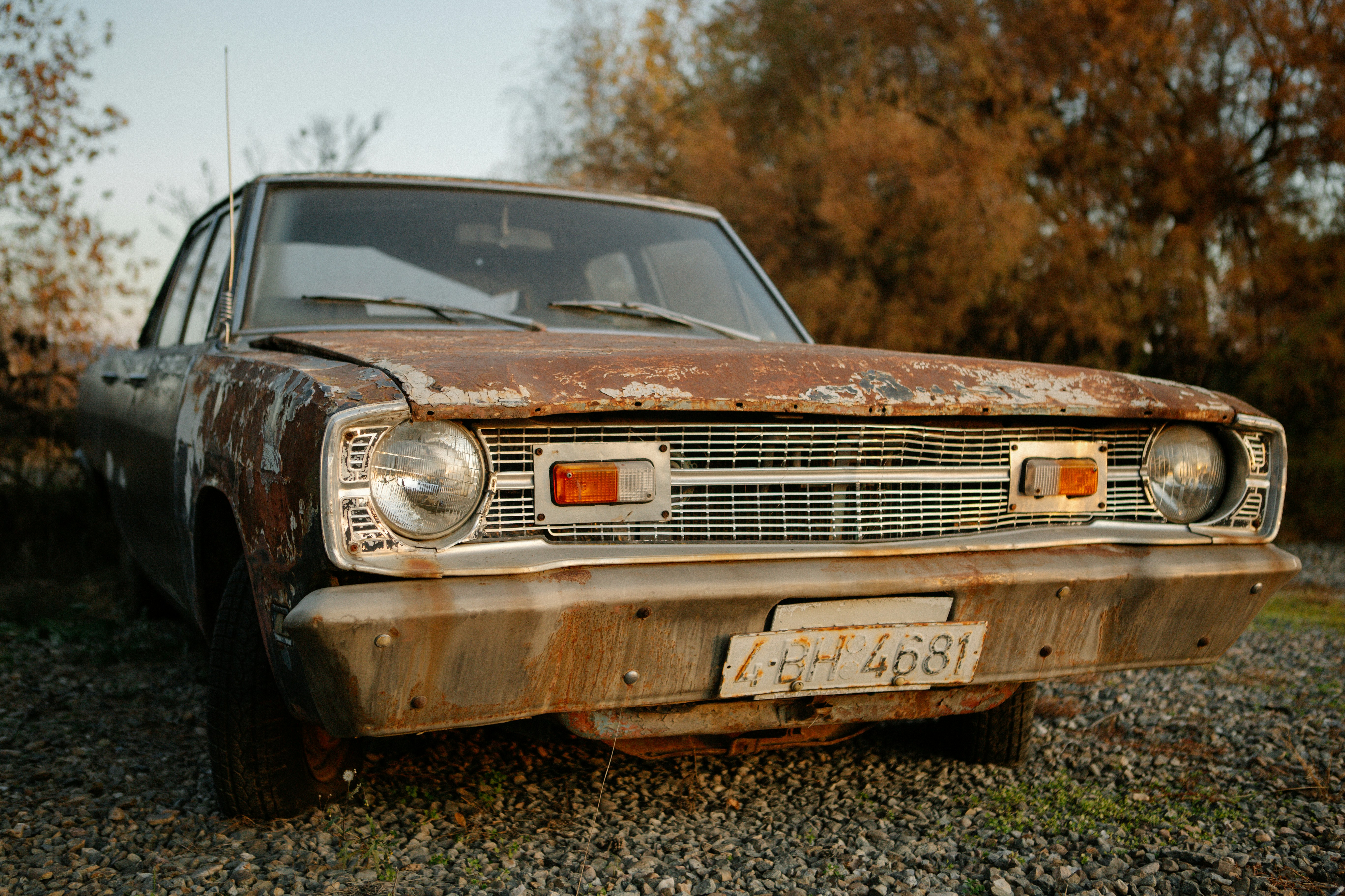 A rusted out car sitting on top of a gravel field photo – Free Car ...