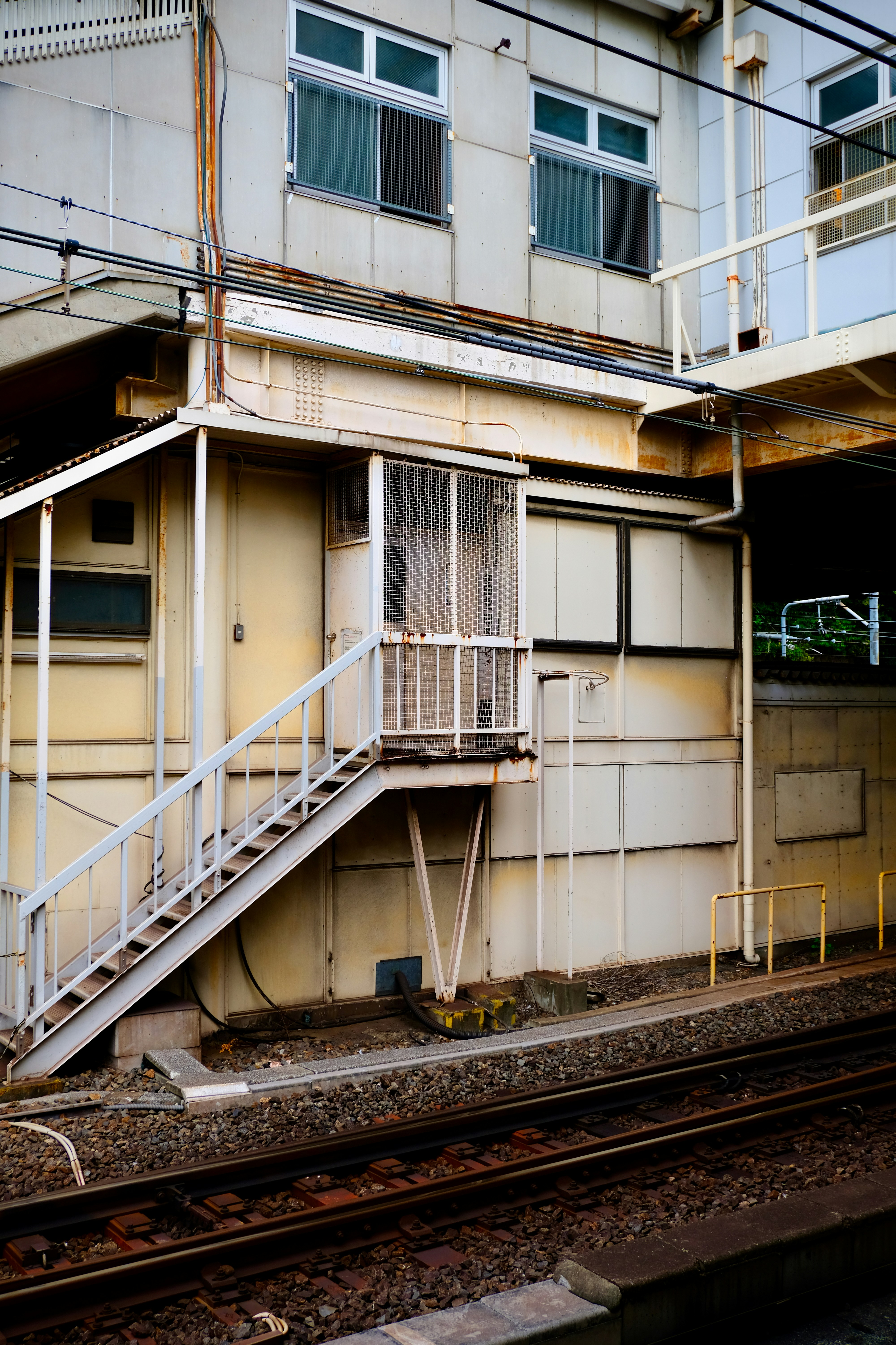 Stairwell by the Tracks: Weathered Facade Under Overhead Wires