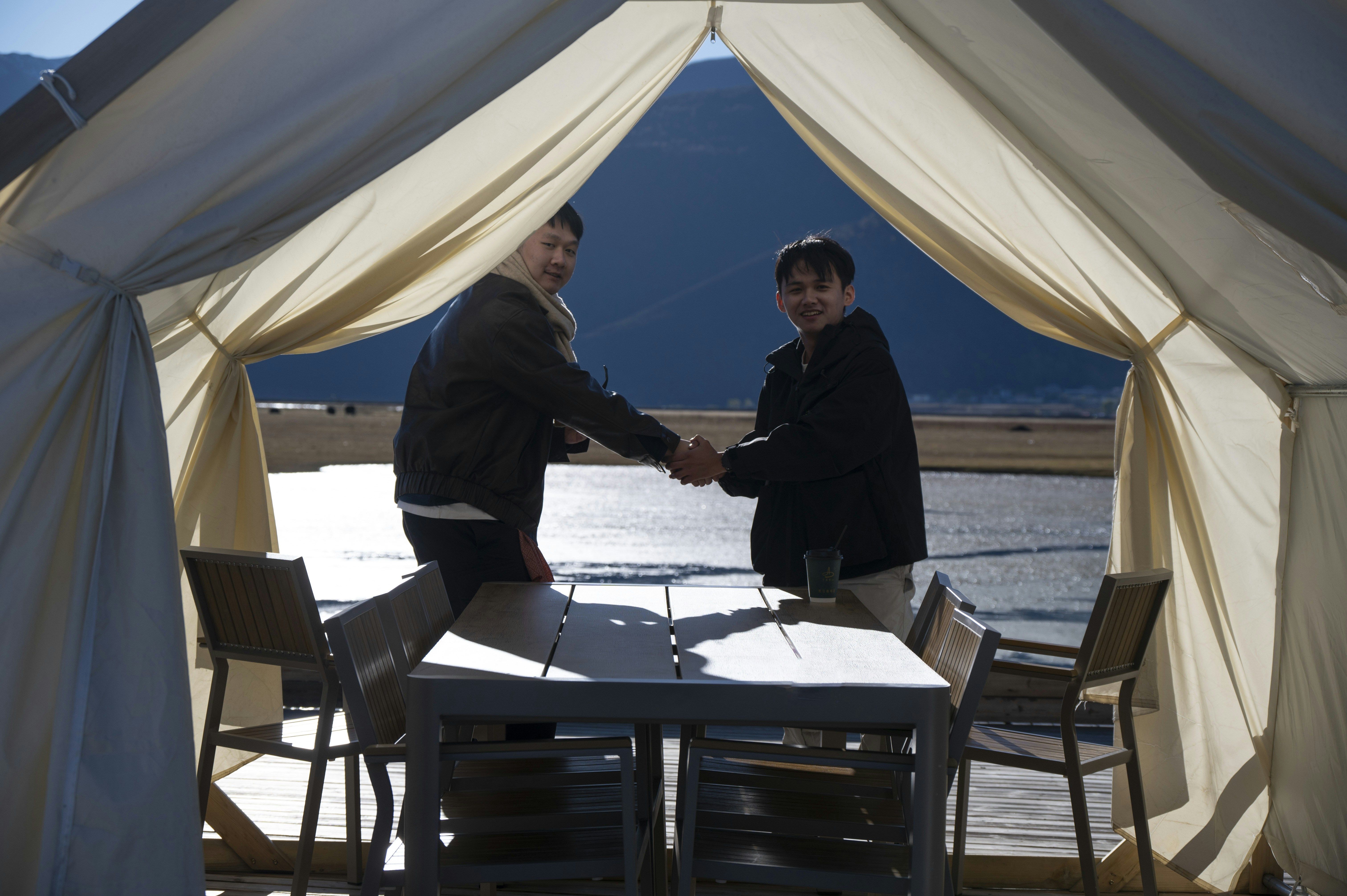 Two men shaking hands over a table in a tent photo – Free 纳帕海 Image on ...