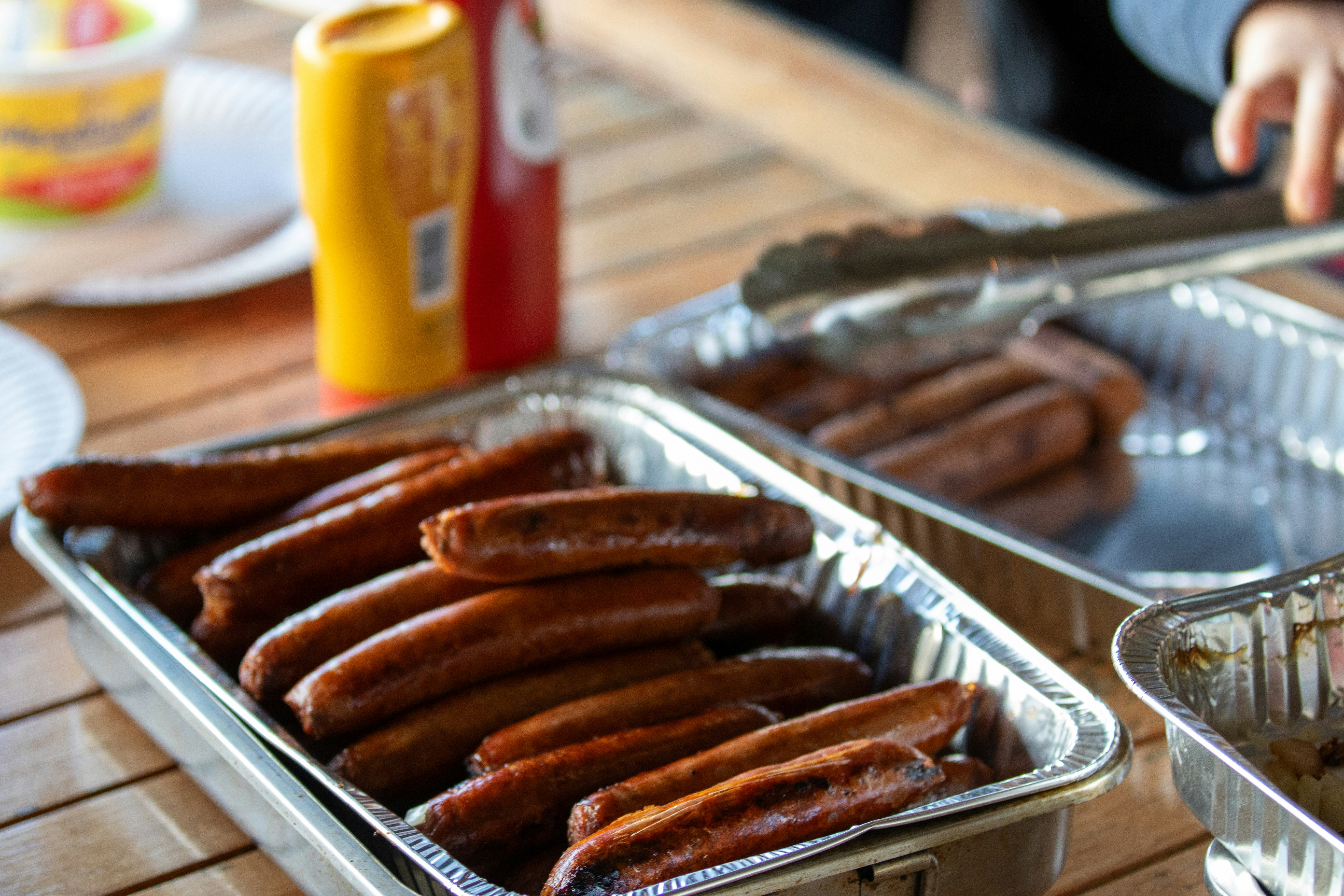 A couple of pans filled with hot dogs on top of a wooden table photo ...