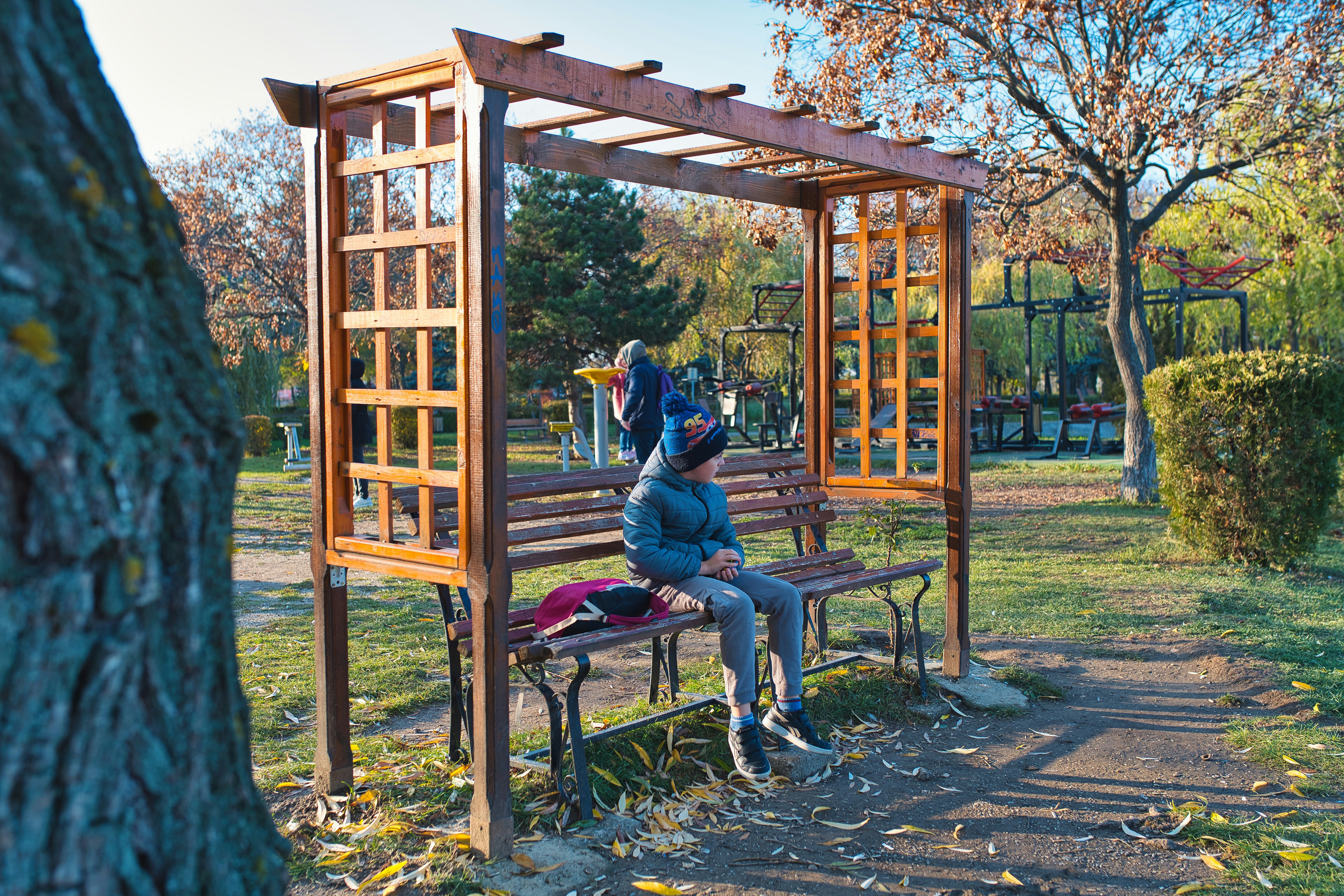 Seated in the Shade: A Quiet Moment Under a Park Pergola