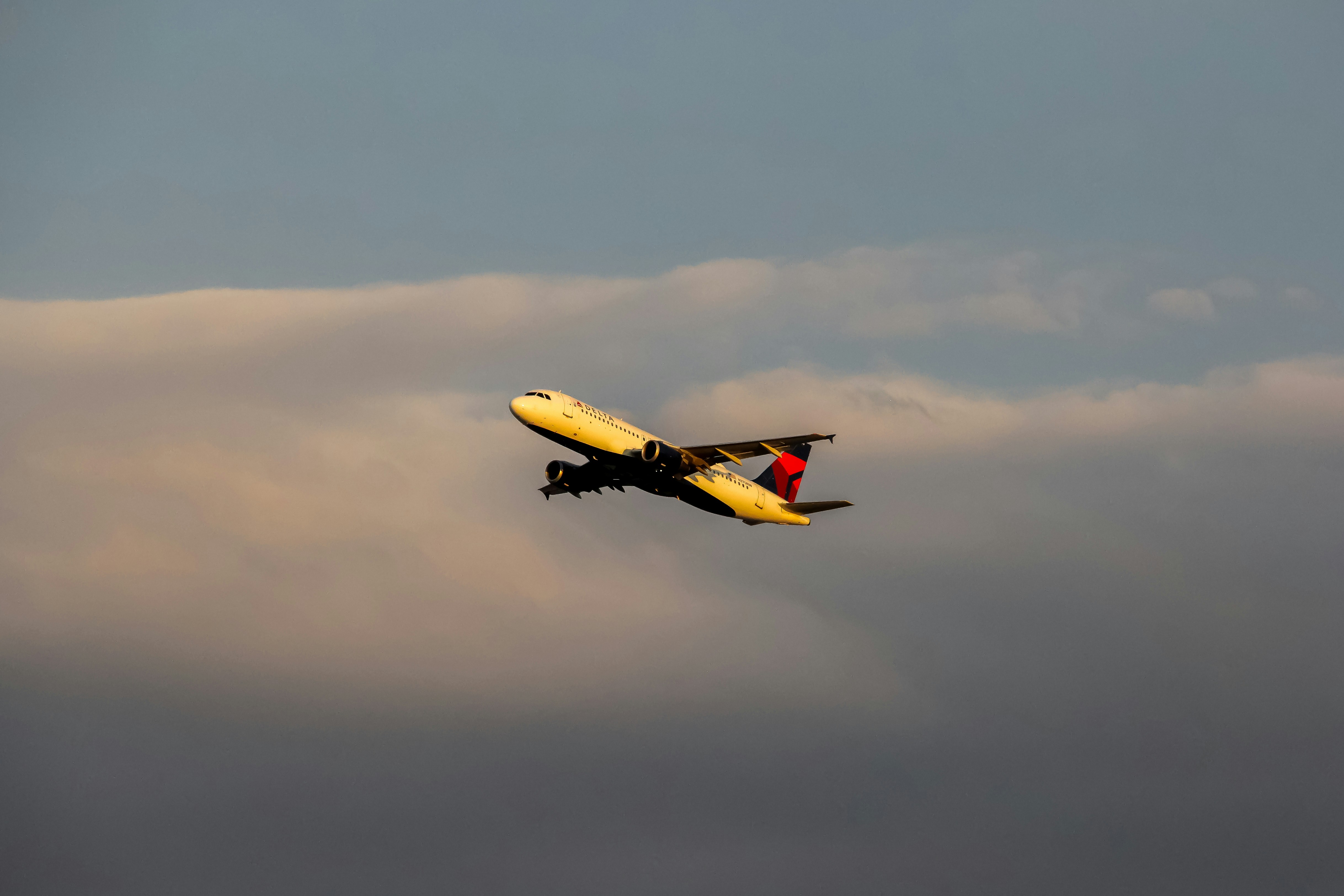 A yellow airplane flying through a cloudy sky photo – Free Dfw airport ...