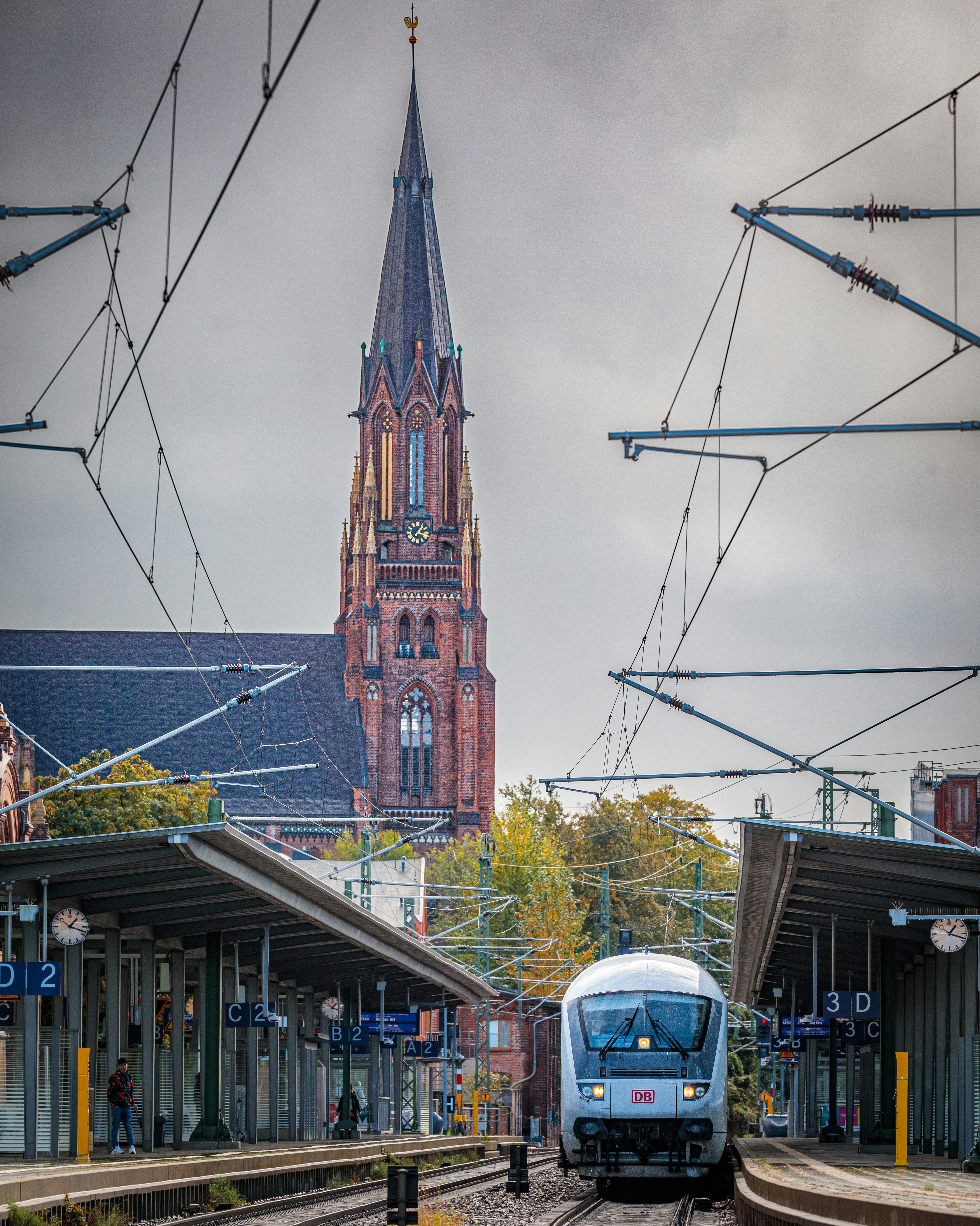 A train traveling down tracks next to a tall building photo – Free ...