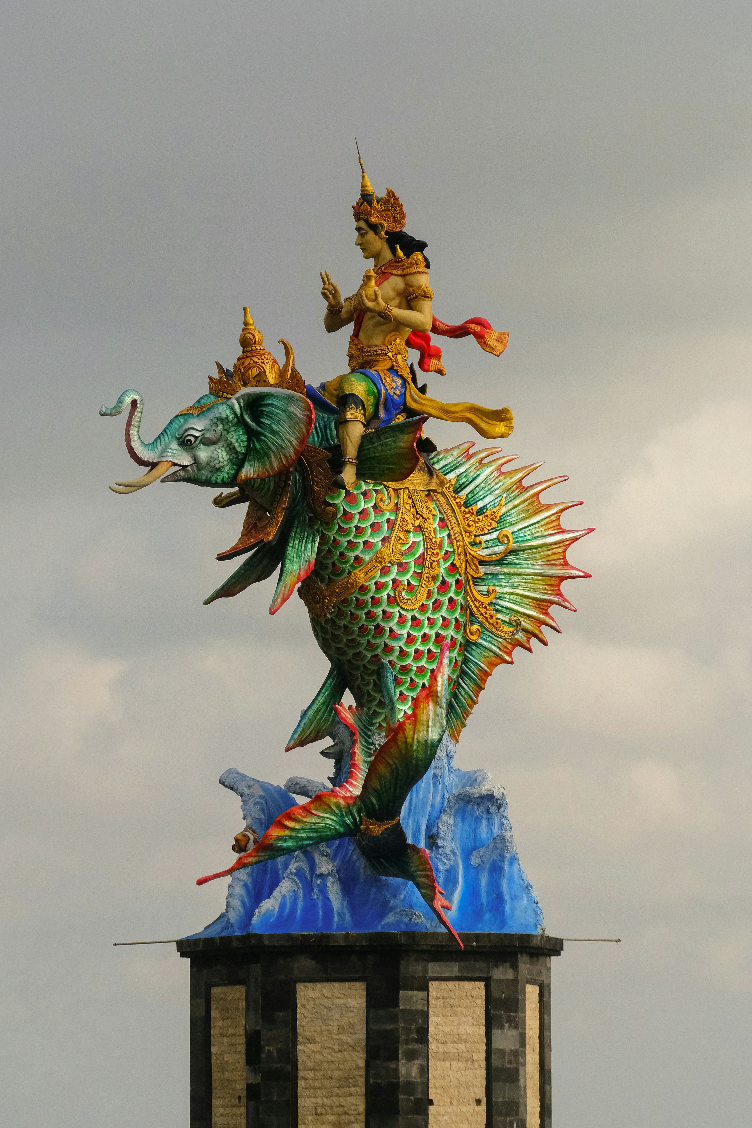A statue of a woman riding a fish on top of a building photo – Free ...