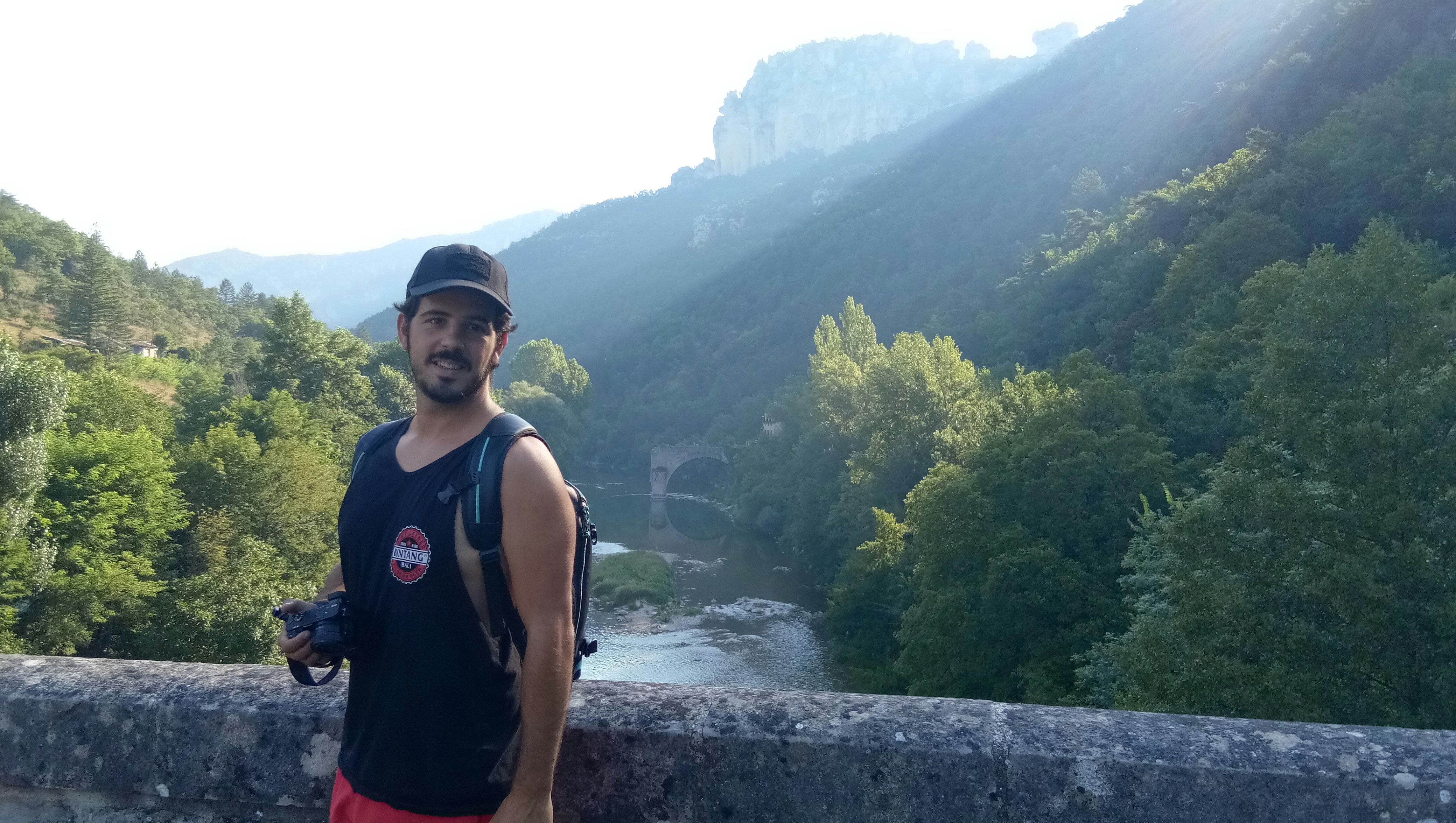Ridge overlook: a lone traveler on a stone railing above a forested valley