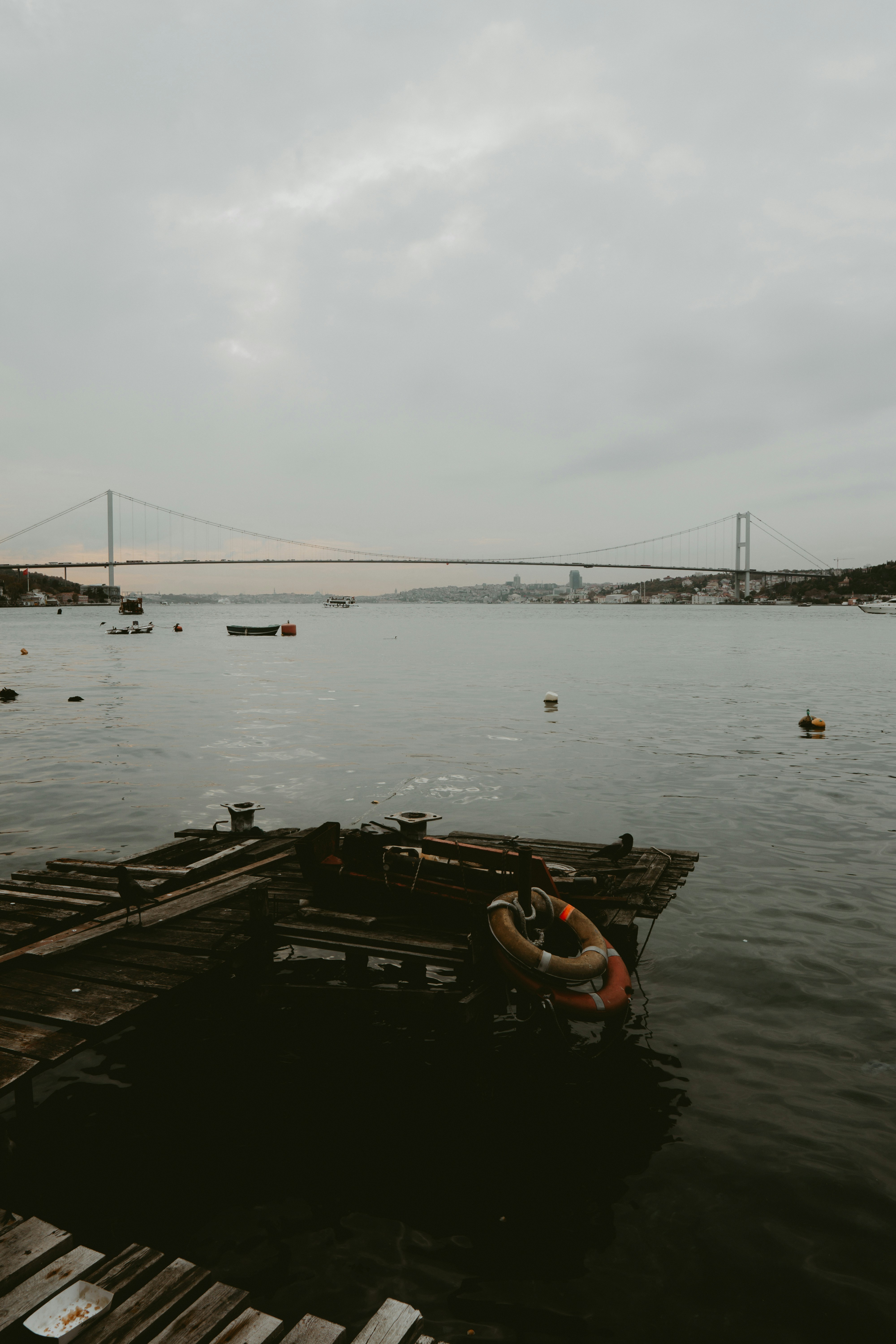 Lifebuoy at the Quiet Dock, Distant Suspension Bridge Under Moody Skies