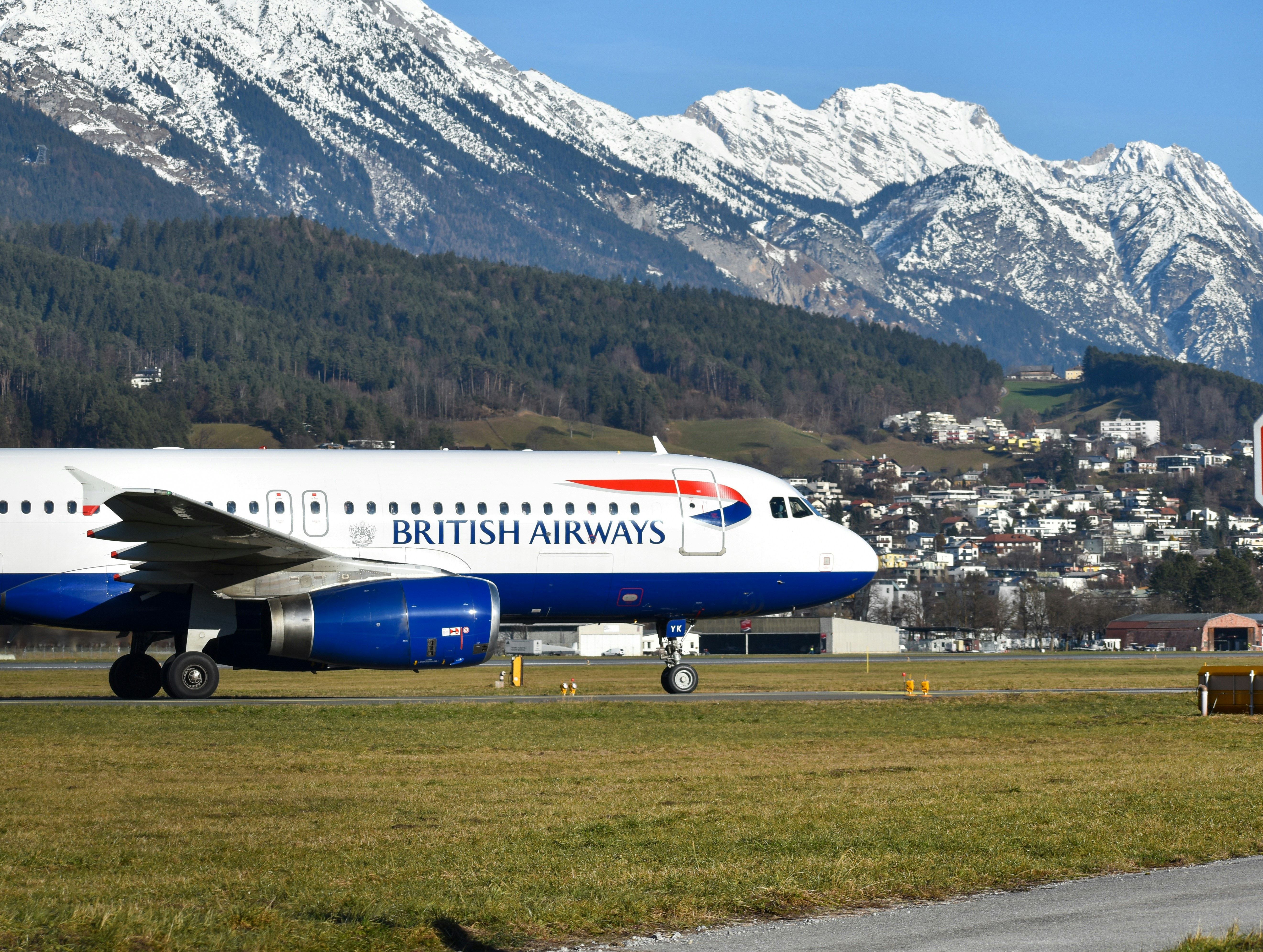 A british airways plane on a runway with mountains in the background ...