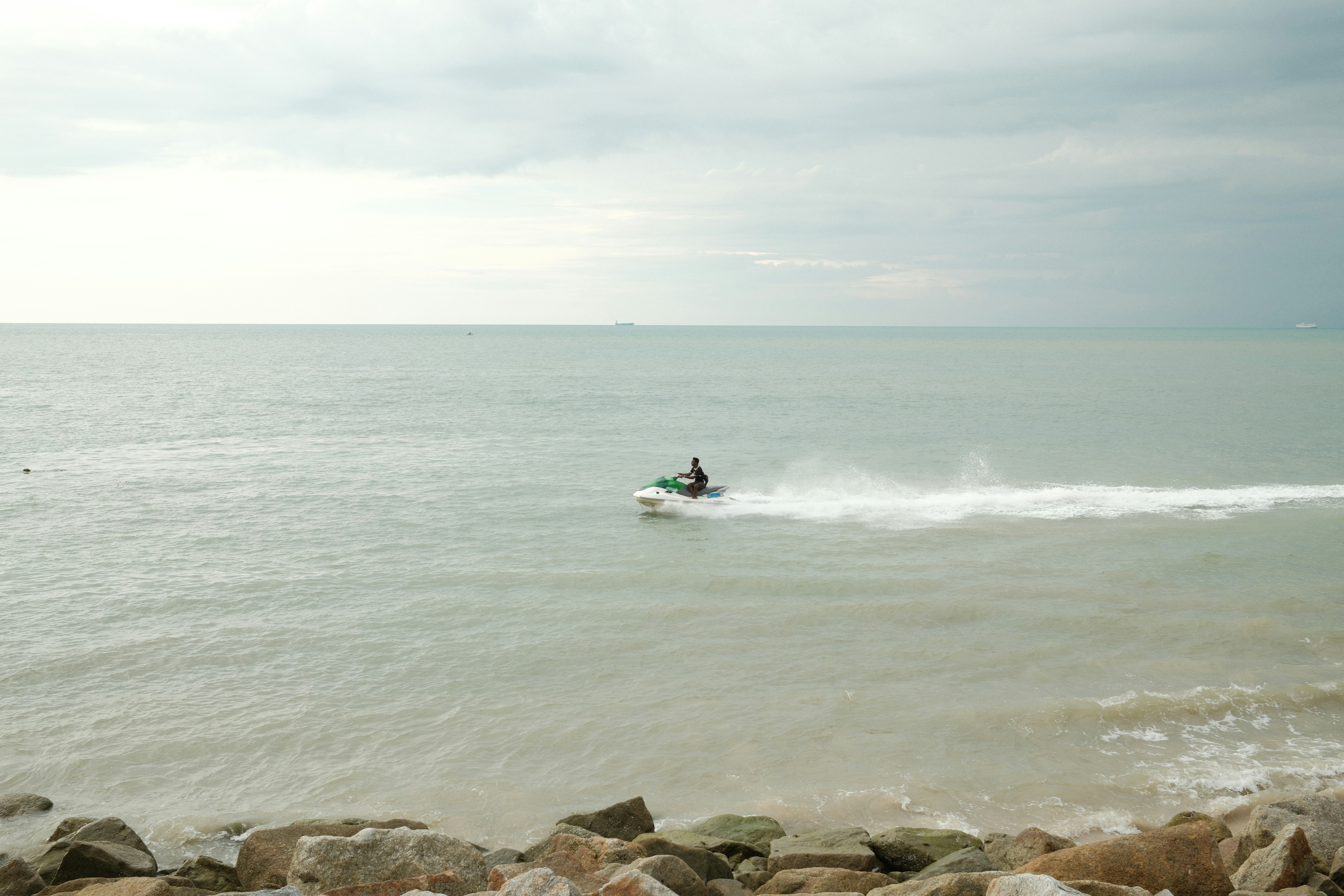Jet Ski Silhouette Skims a Quiet Atlantic by a Rocky Shore