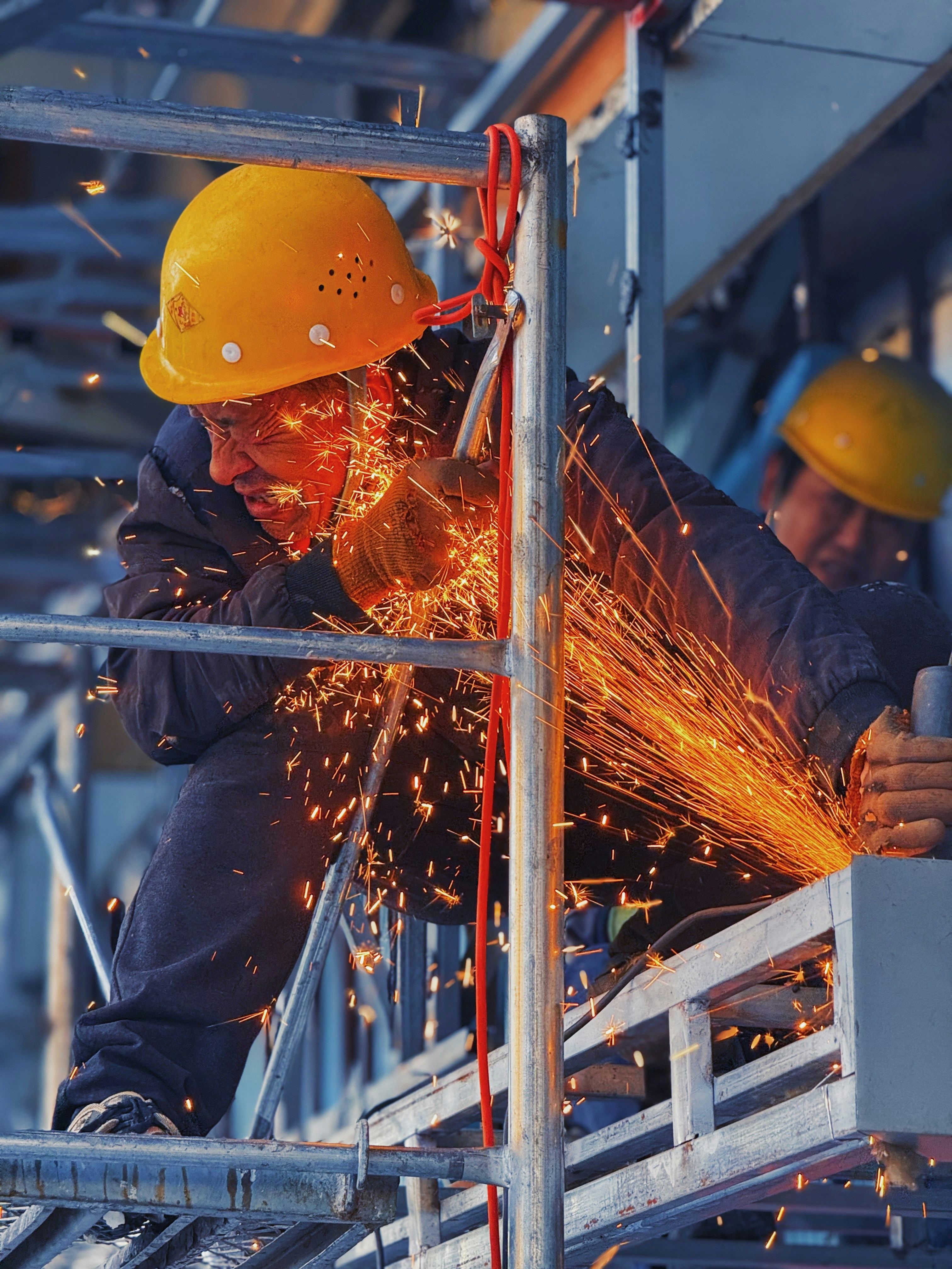 A man in a hard hat grinding metal with a grinder photo – Free City ...