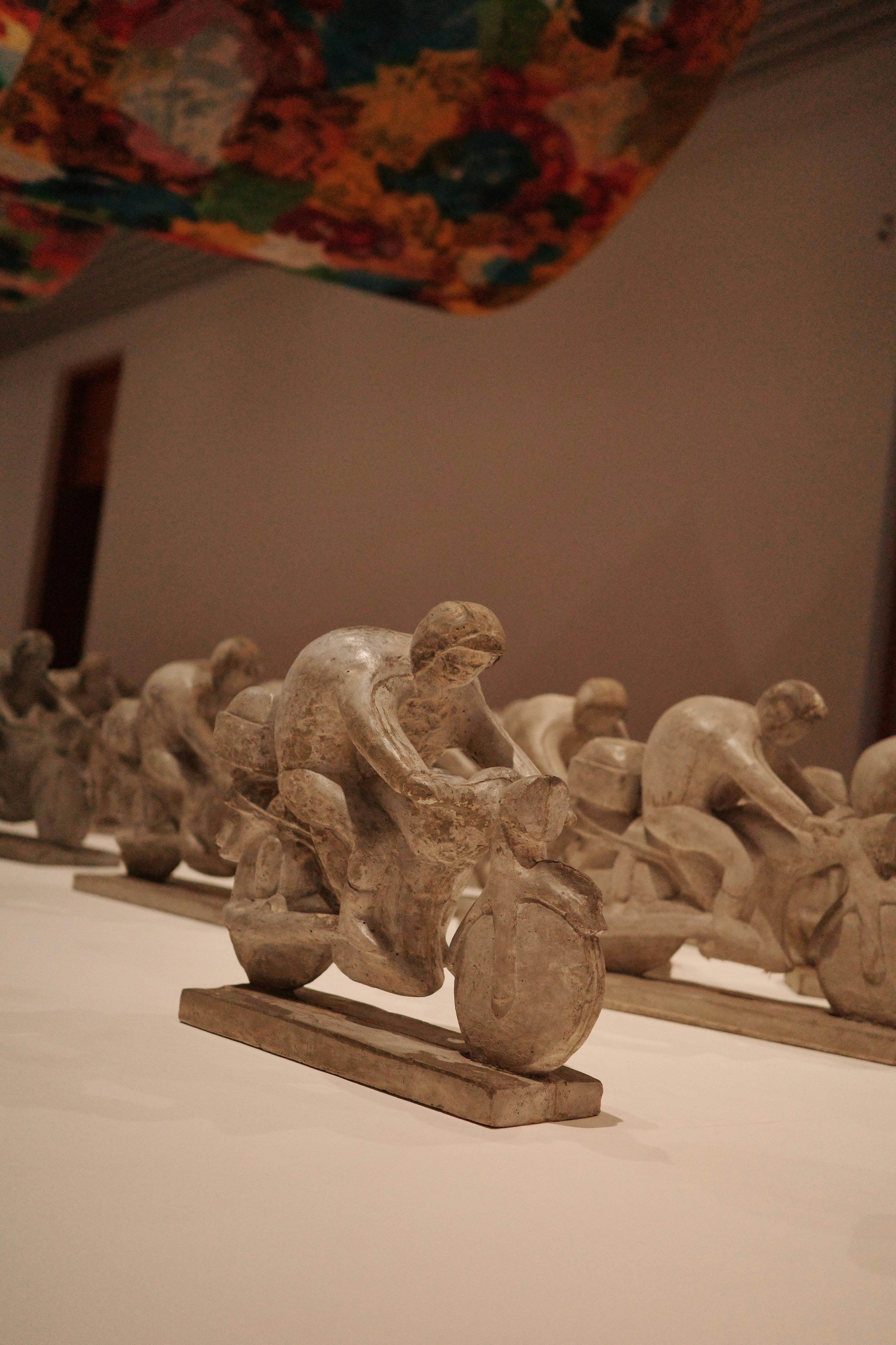 Line of Tiny Cyclists: A Row of Earthen Motorcycles in a Gallery