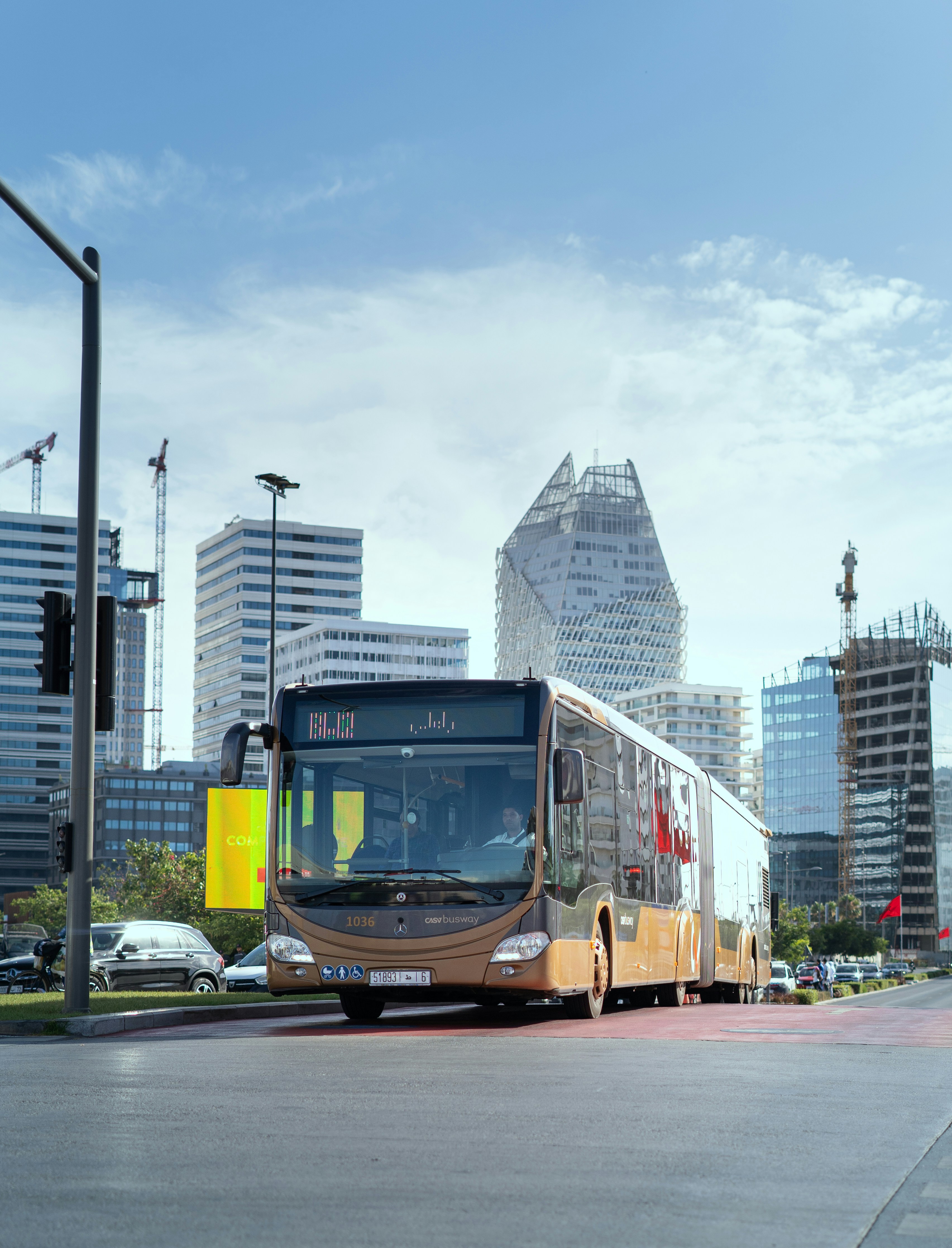 A large bus driving down a street next to tall buildings photo – Free ...