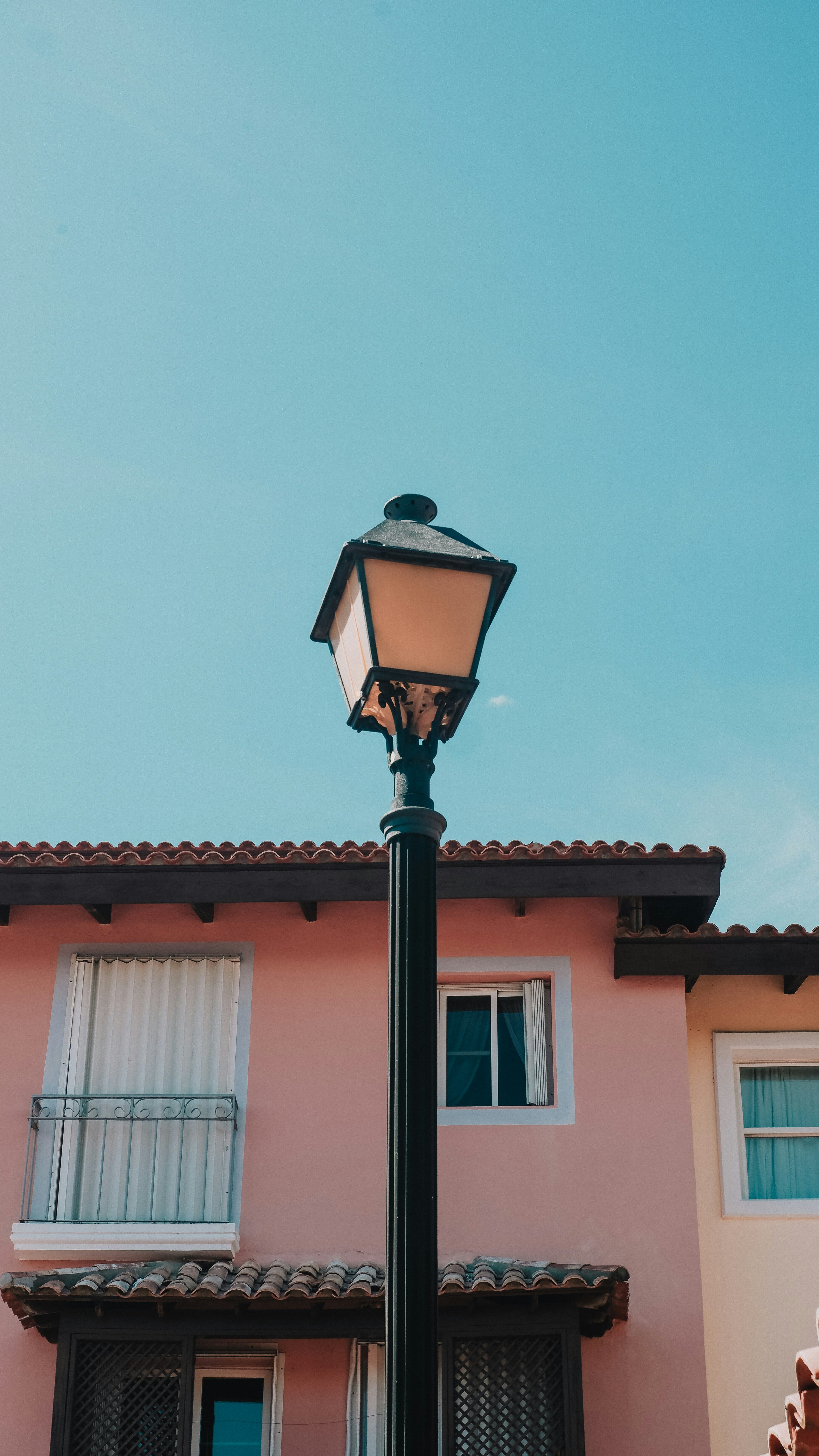 A lamp post in front of a pink building photo – Free Lamp post Image on ...