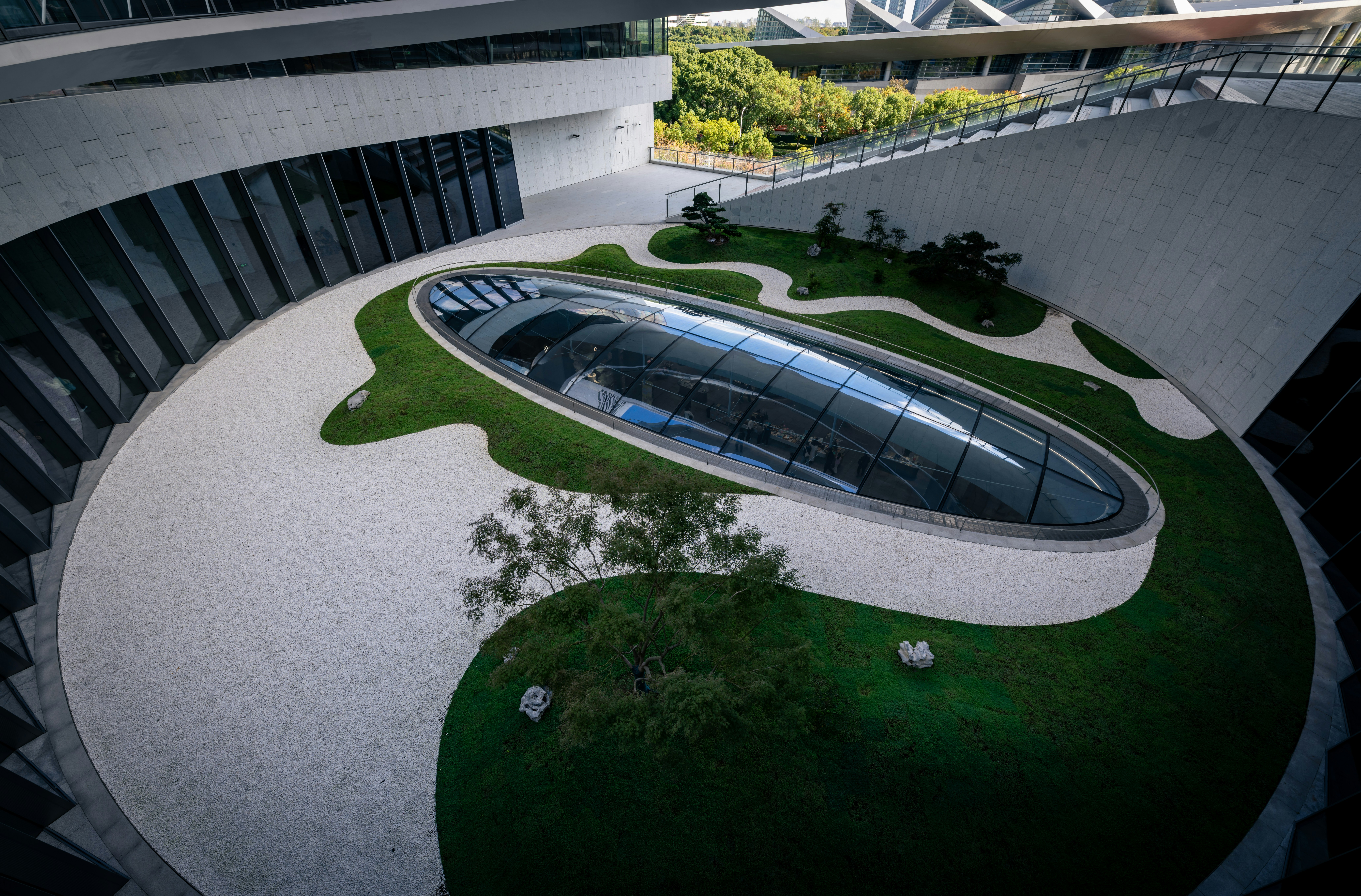 Glass-Encased Atrium Framed by Curved White Gravel