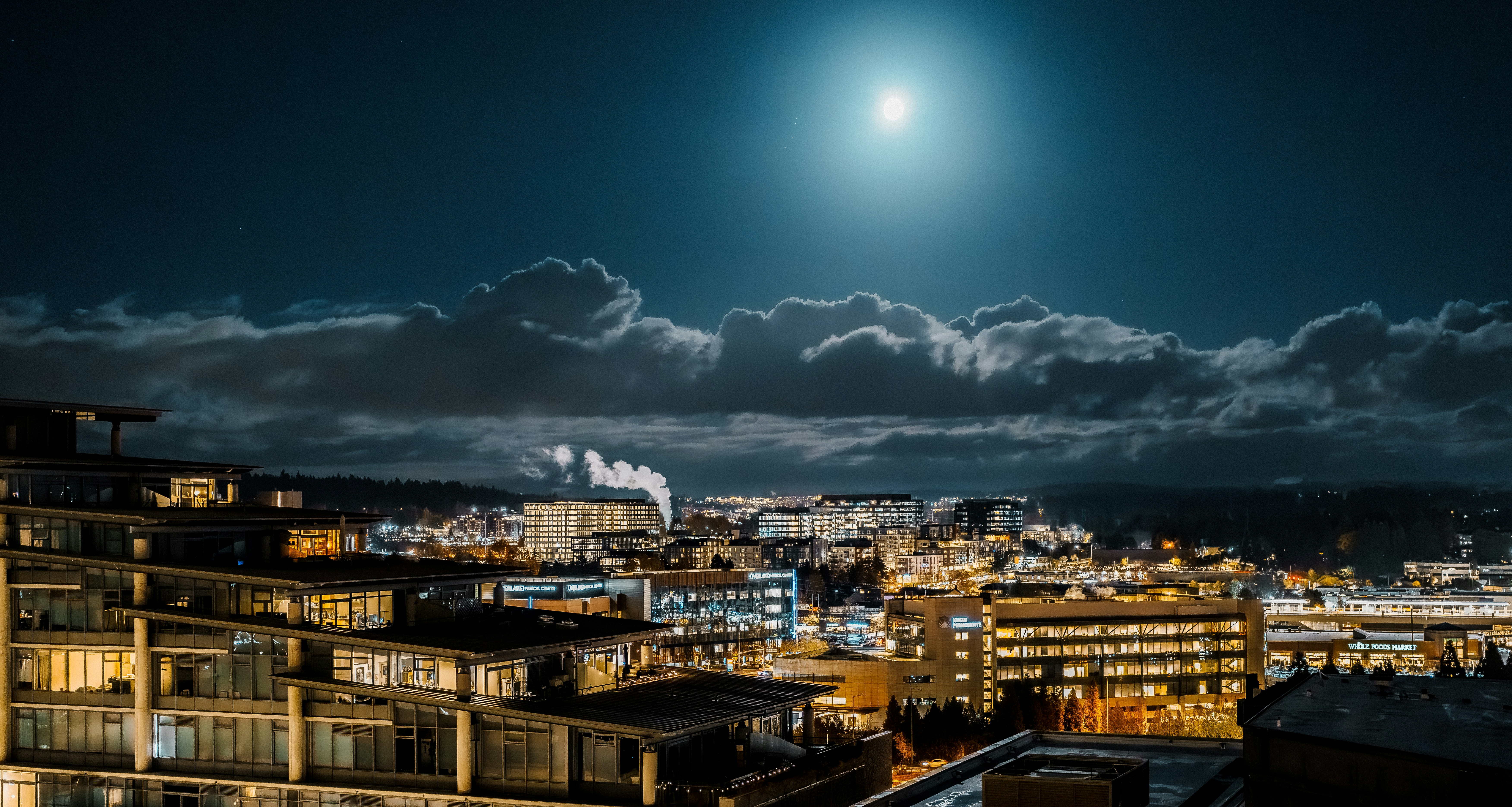Moon Over a Quiet Metropolis: Night Glow Beneath Cloud-Lit Skyscrapers