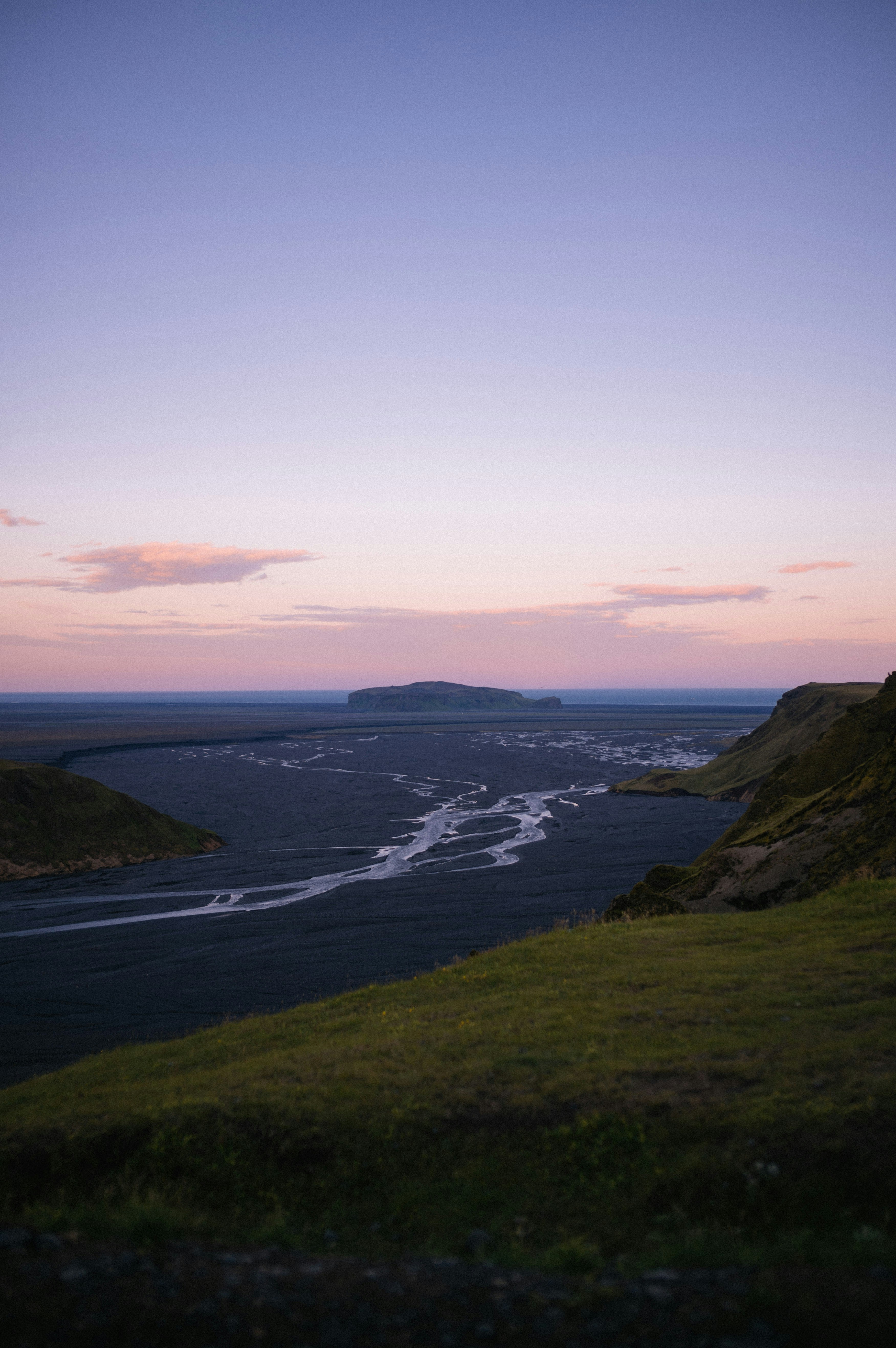 Winding river through lush valleys under a twilight sky transitioning from blue to pink.