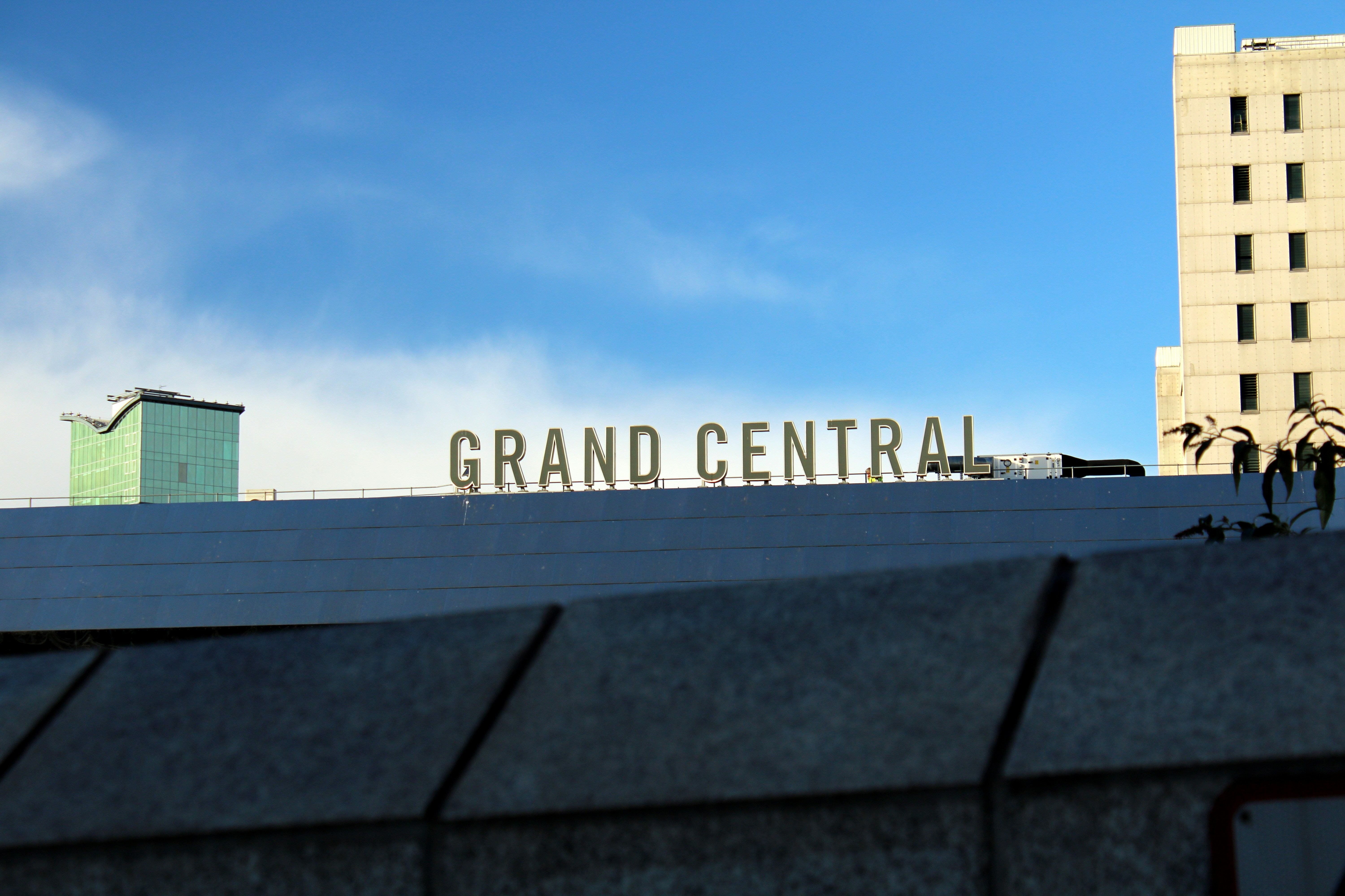 Grand Central Letters Hover Above a Rooftop Wall Under a Clear Blue Sky