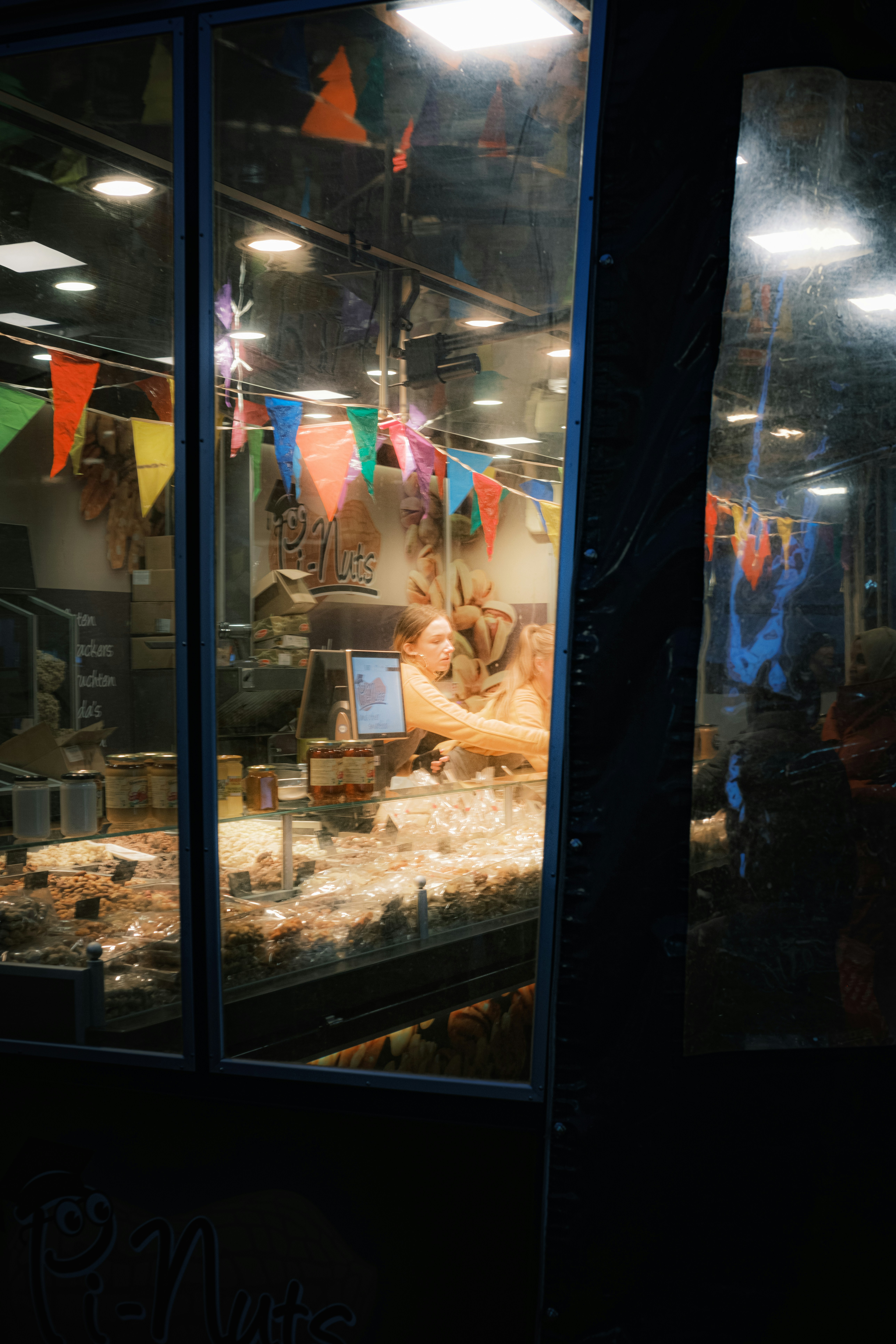 Night Window Bakery: Pastries Behind Glass Under Festive Flags