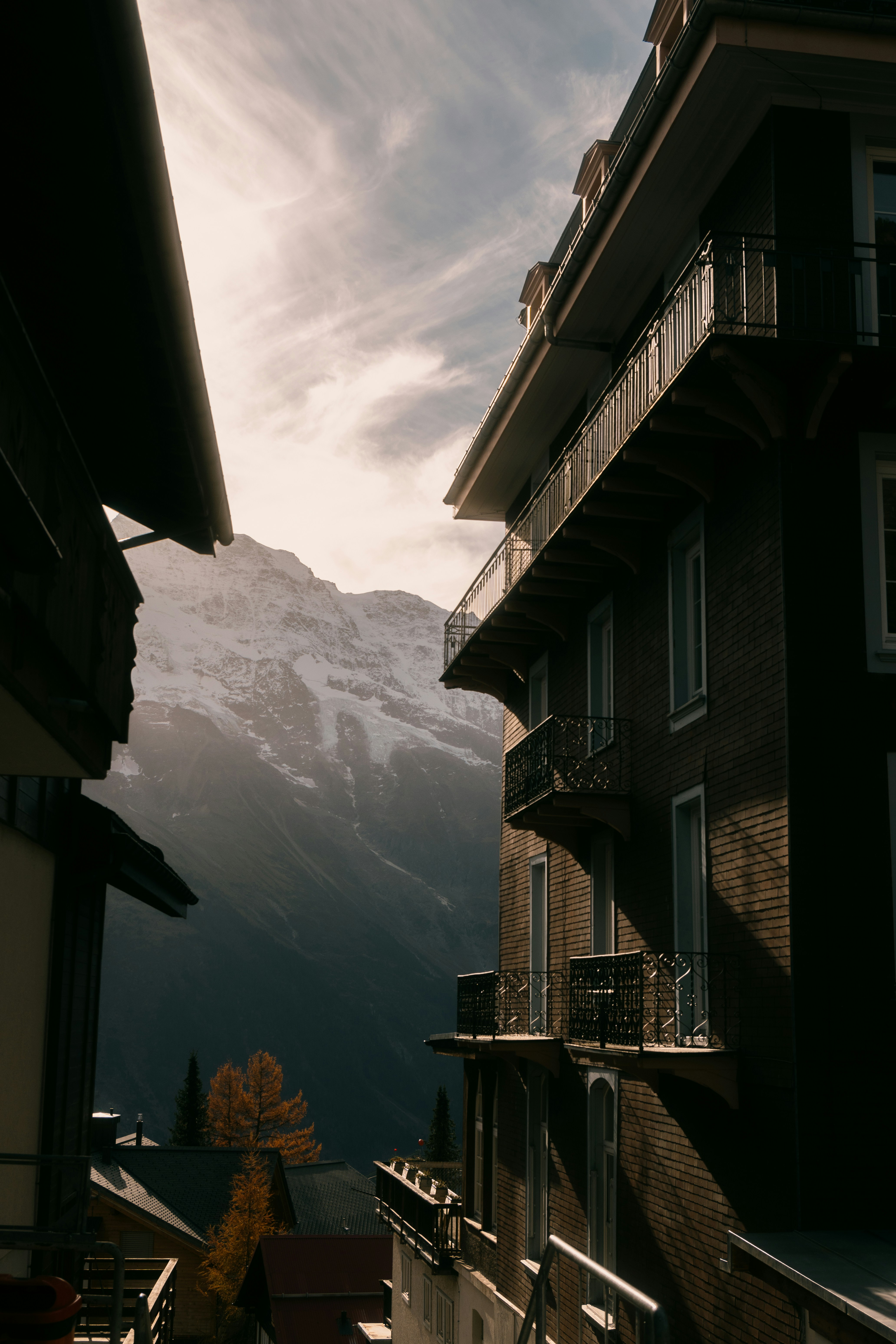 Sunlit Alpine Gap: Narrow Street Framing Snowcapped Peaks