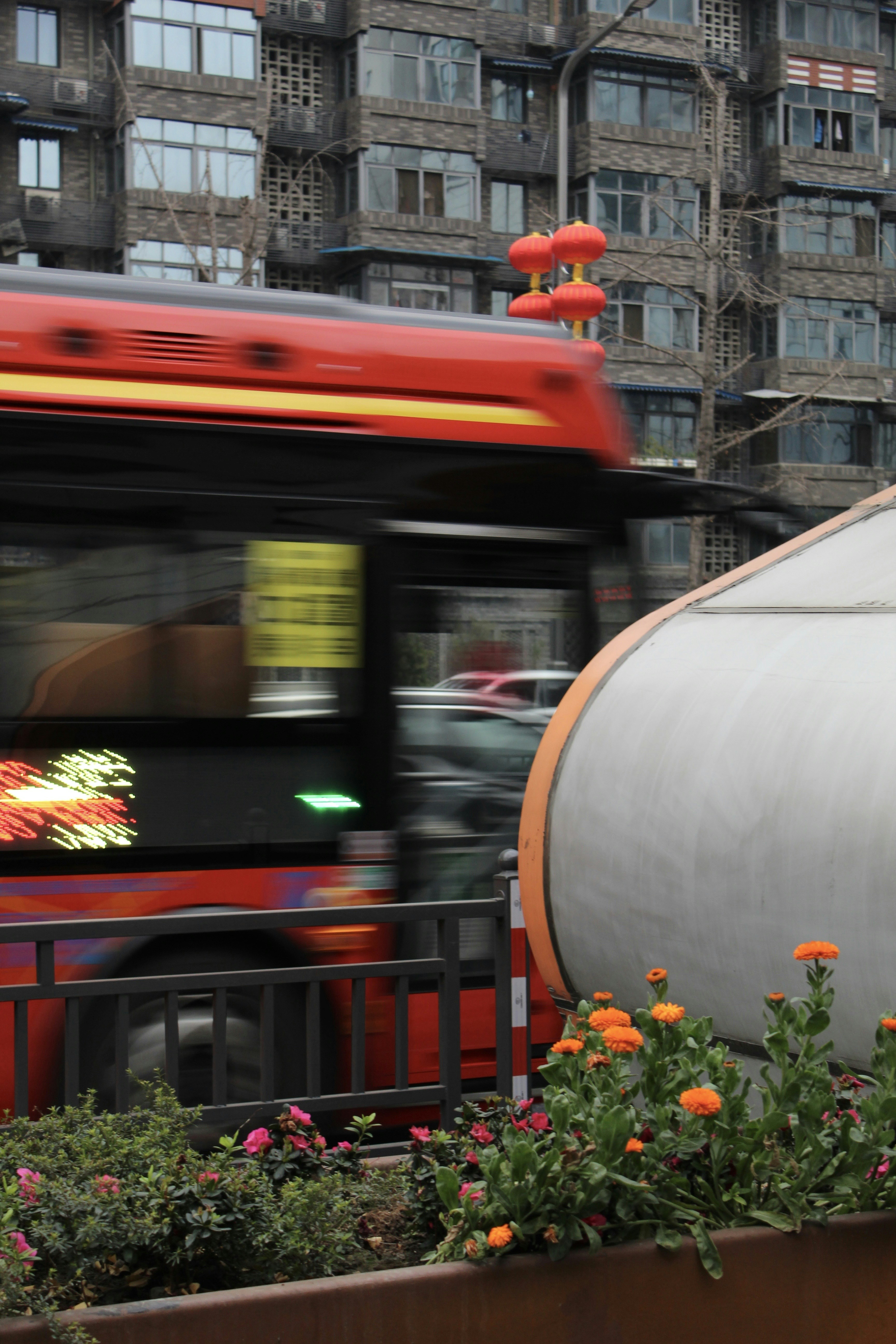 Urban Motion Blur: A Red City Bus Rushing Past Flower Planters