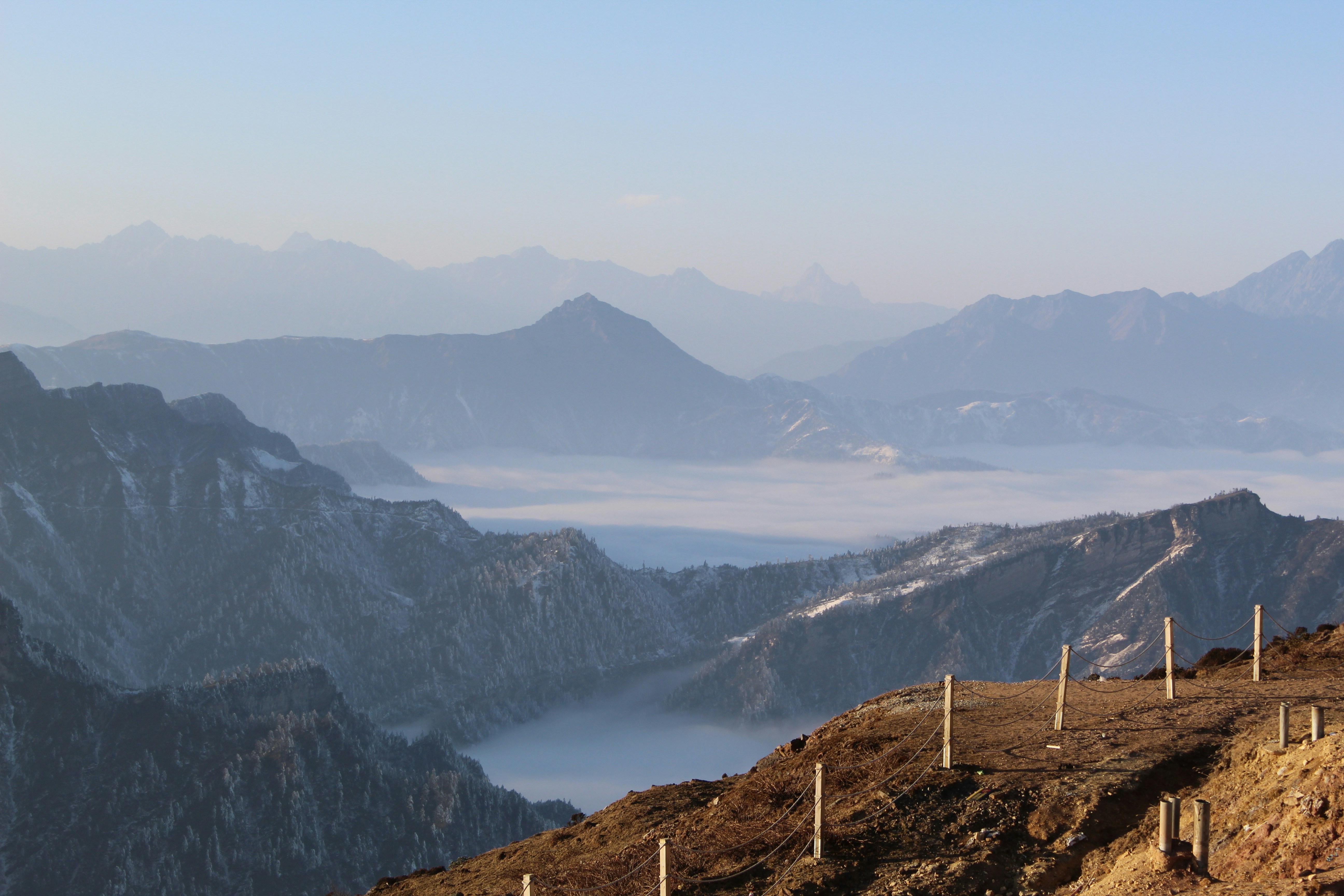 A man standing on top of a mountain next to a lush green hillside