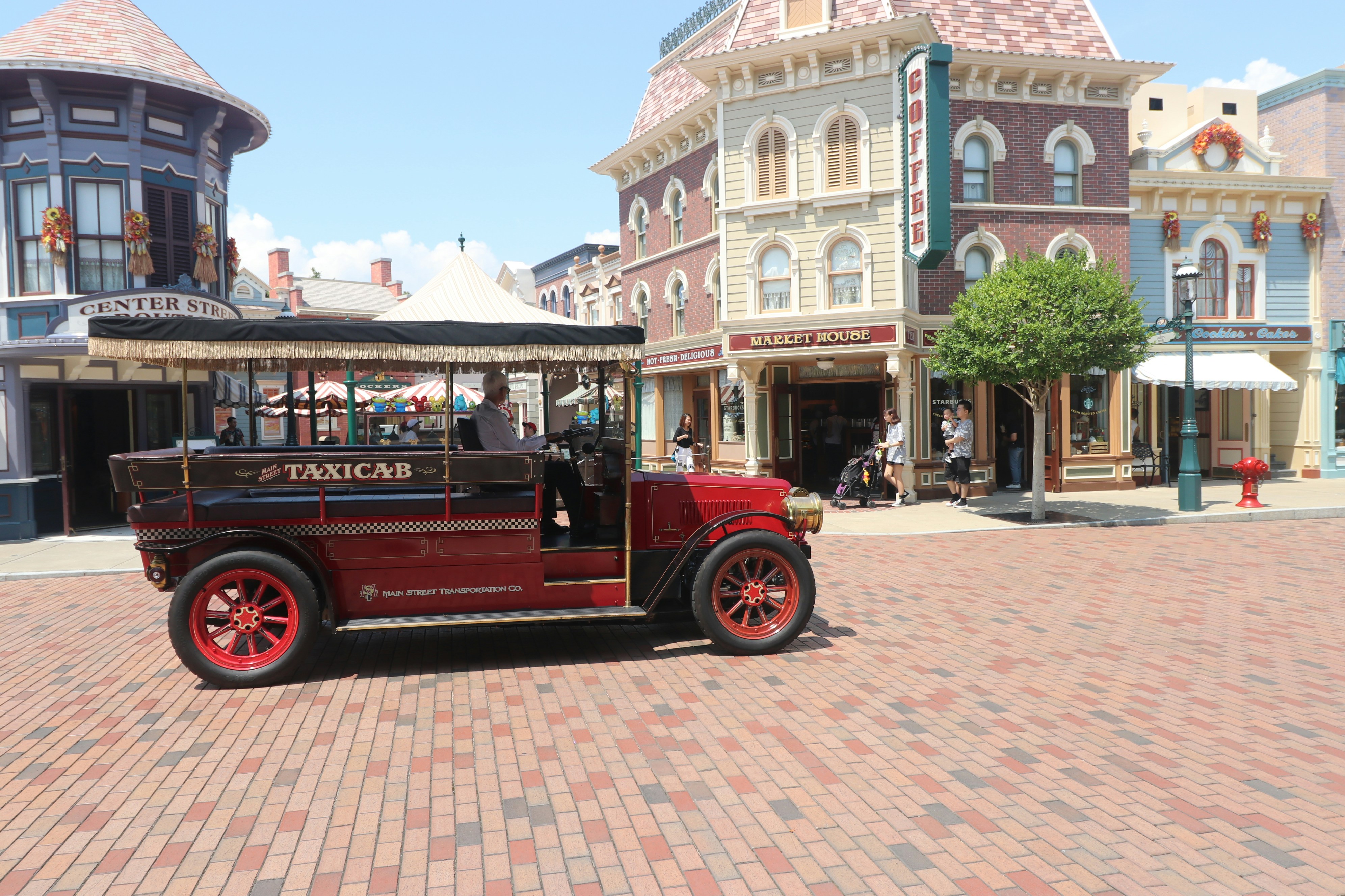 Red Vintage Taxi Anchors a Bright Brick Plaza in a Whimsical Town Square