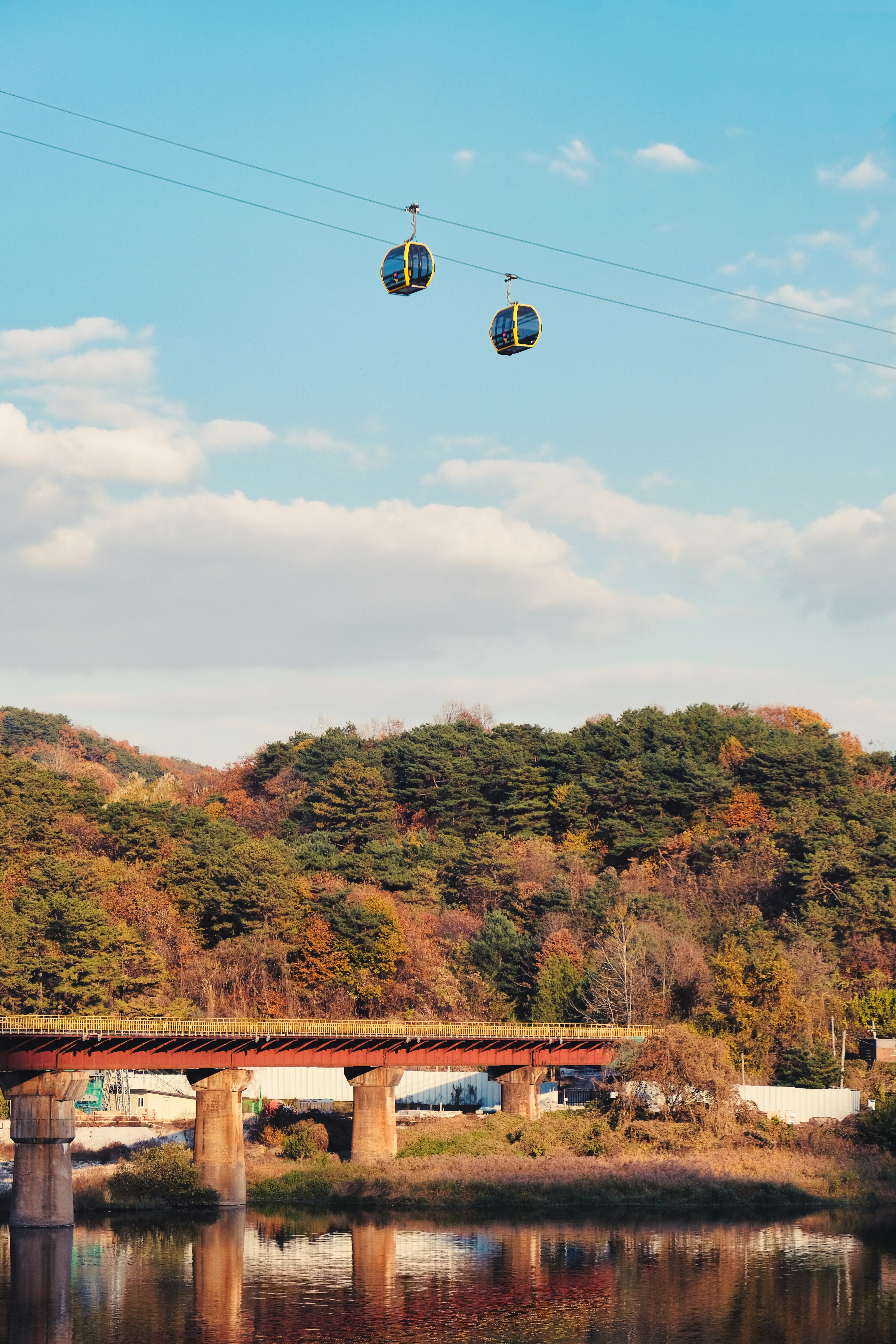 Twin Cable Cars Glide Over a Quiet Autumn River Valley