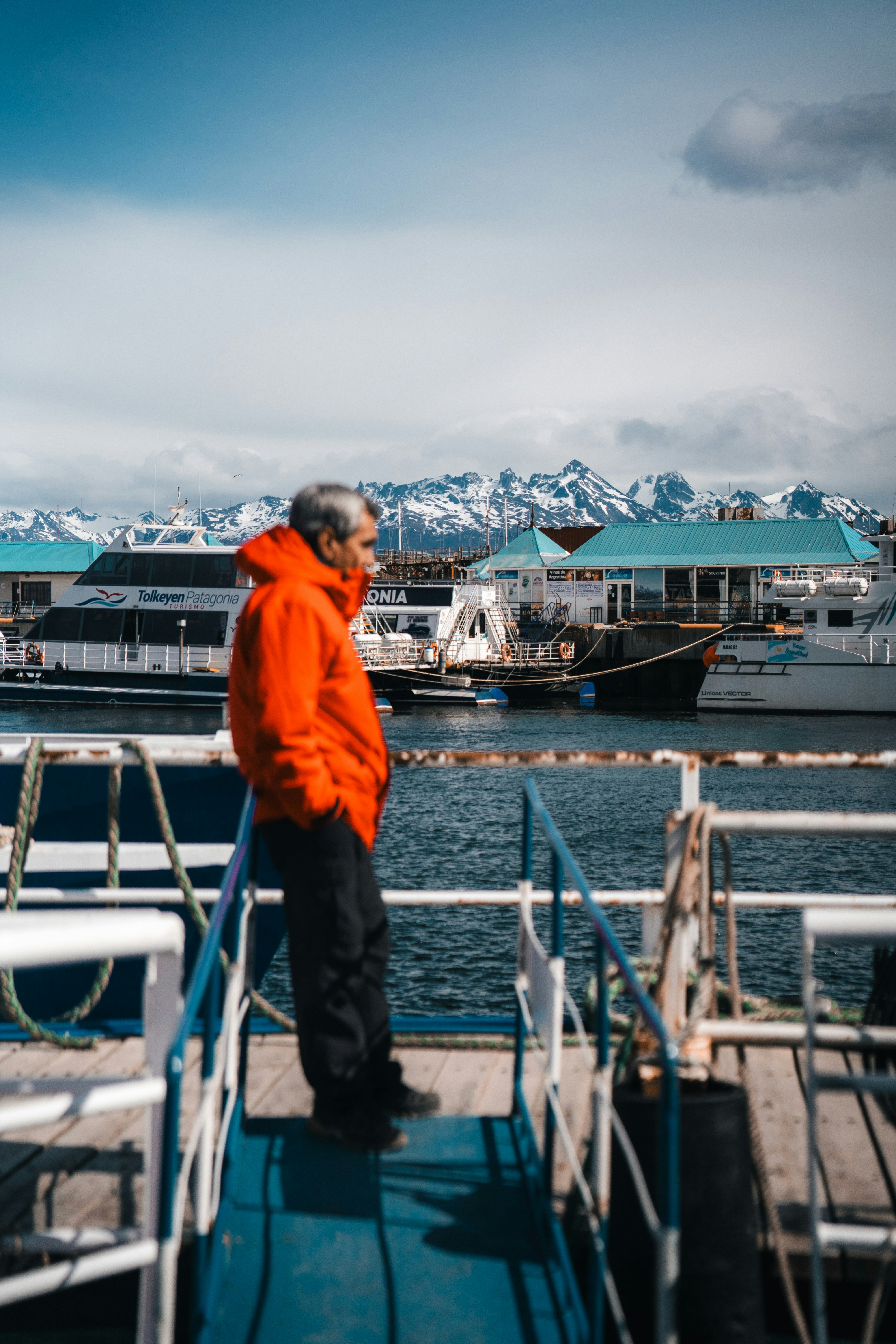 Crimson Jacket at the Dock: Harbor Portrait with Snow-kissed Peaks