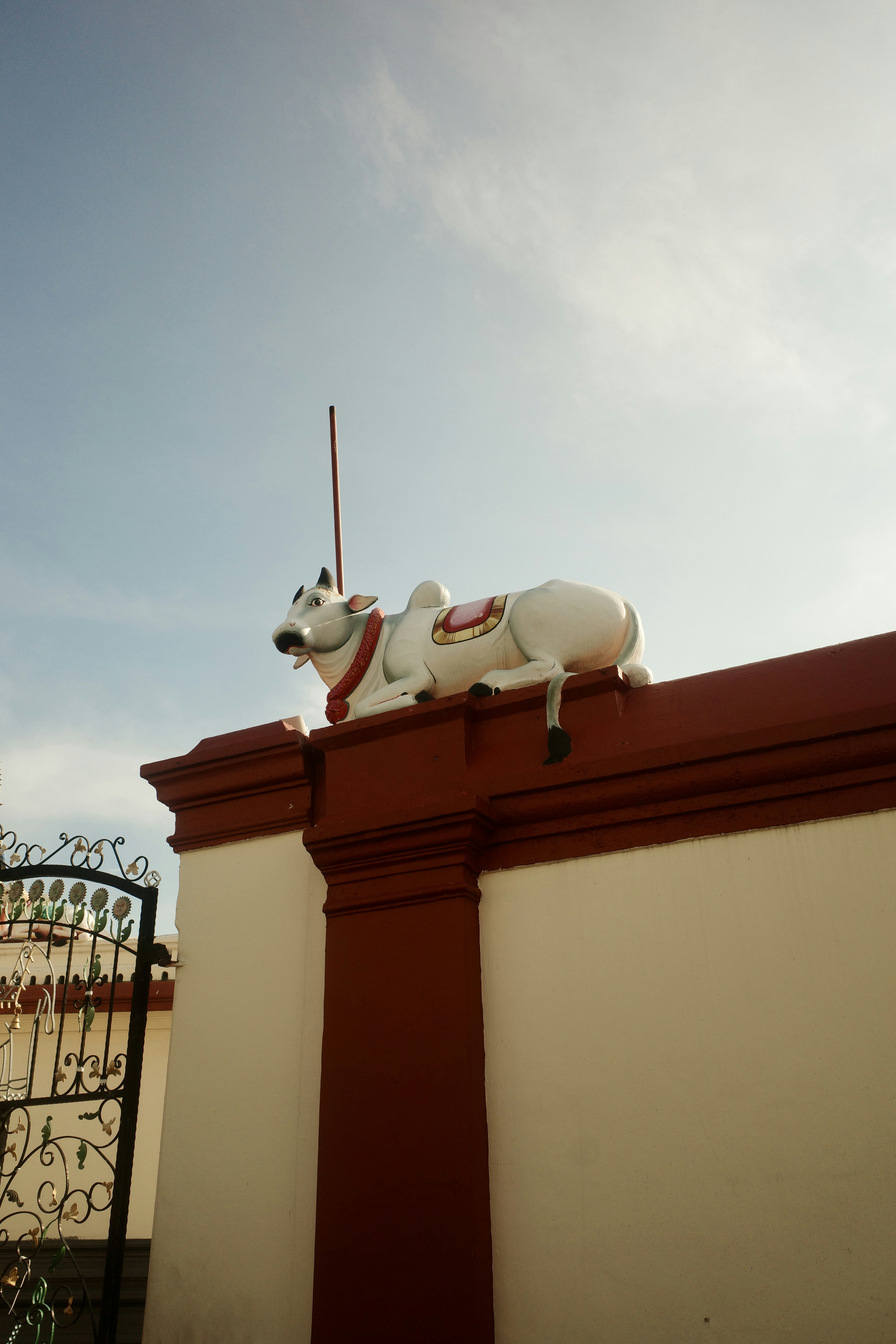 White Sentinel on a Crimson Parapet Under a Quiet Blue Sky