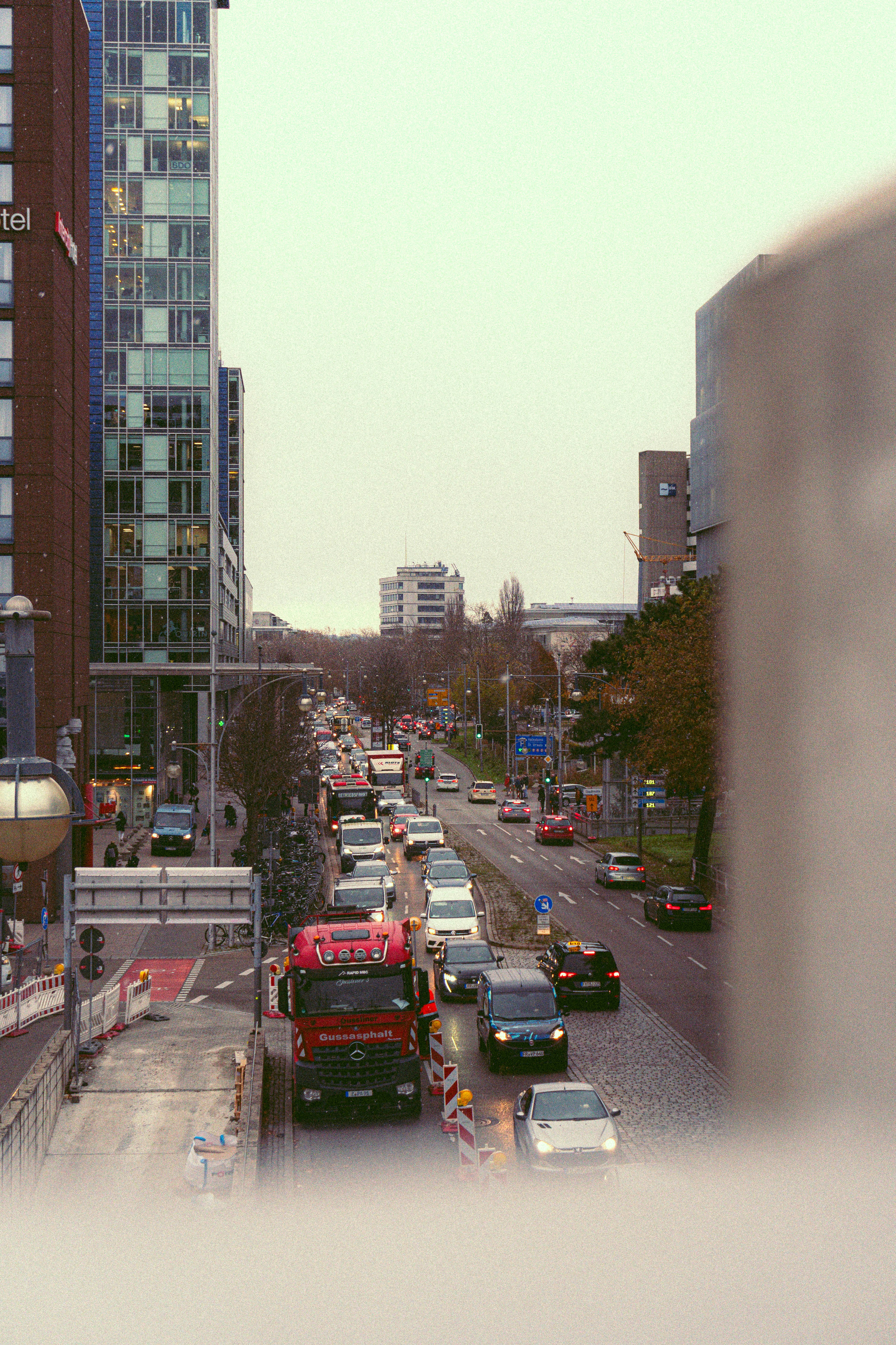 Red Truck Anchors a Busy City Street Framed by Glass Towers