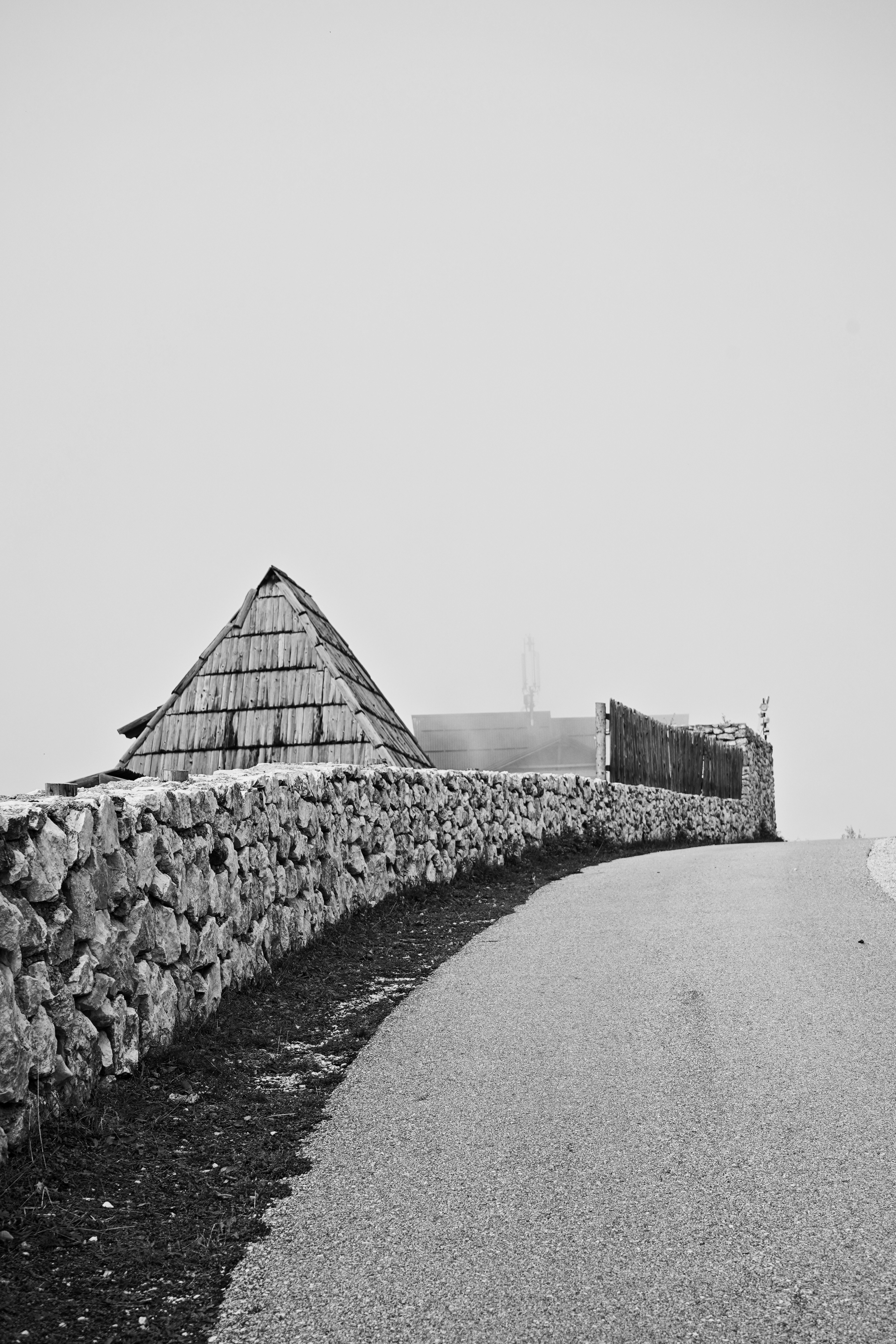 Curve of Stones and a Thatched Roof: A Quiet Horizon Along a Dry-Stone Wall