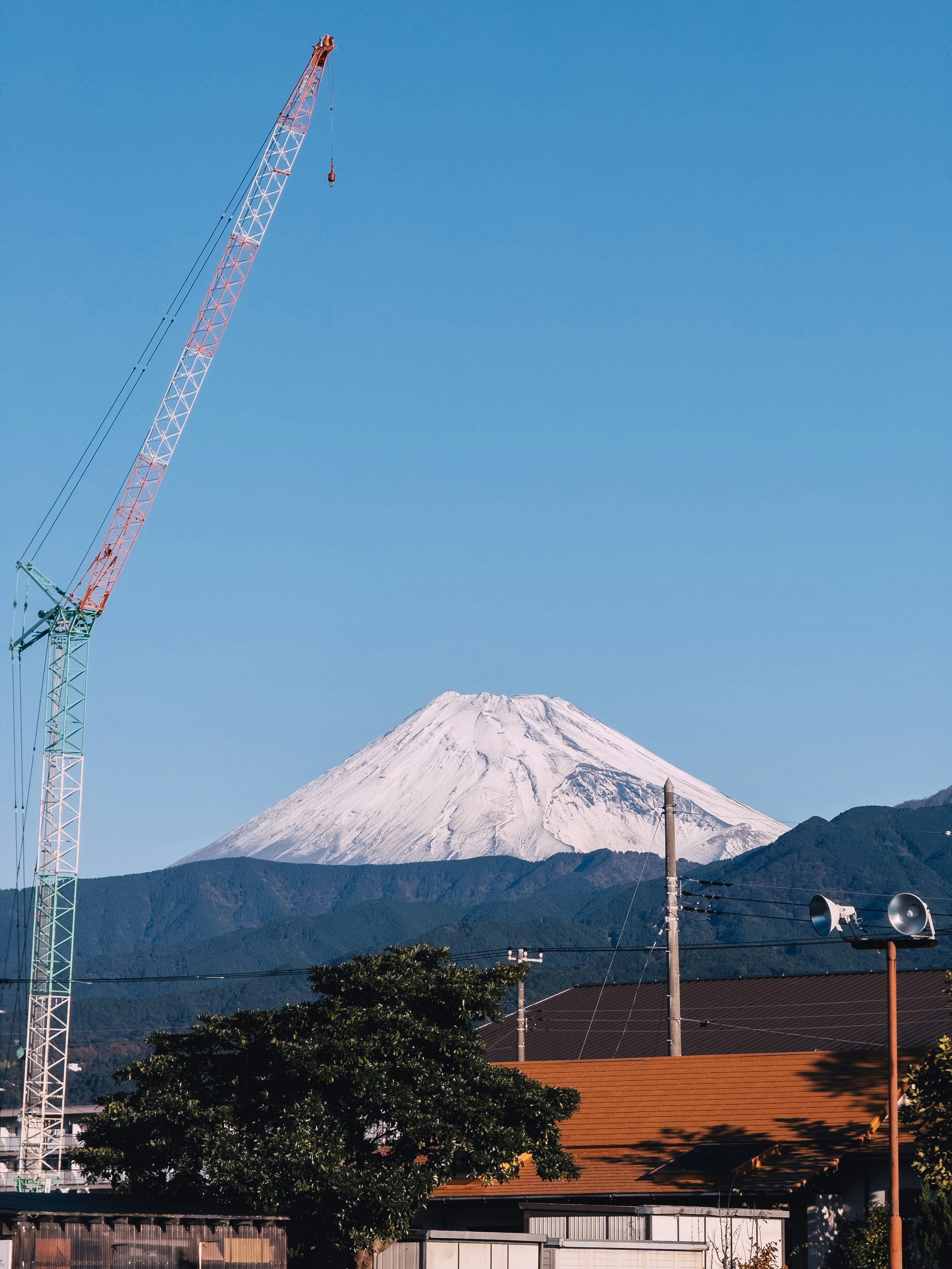 Crane Diagonal Framing a Fuji-like Snowcap under a Pristine Blue Sky