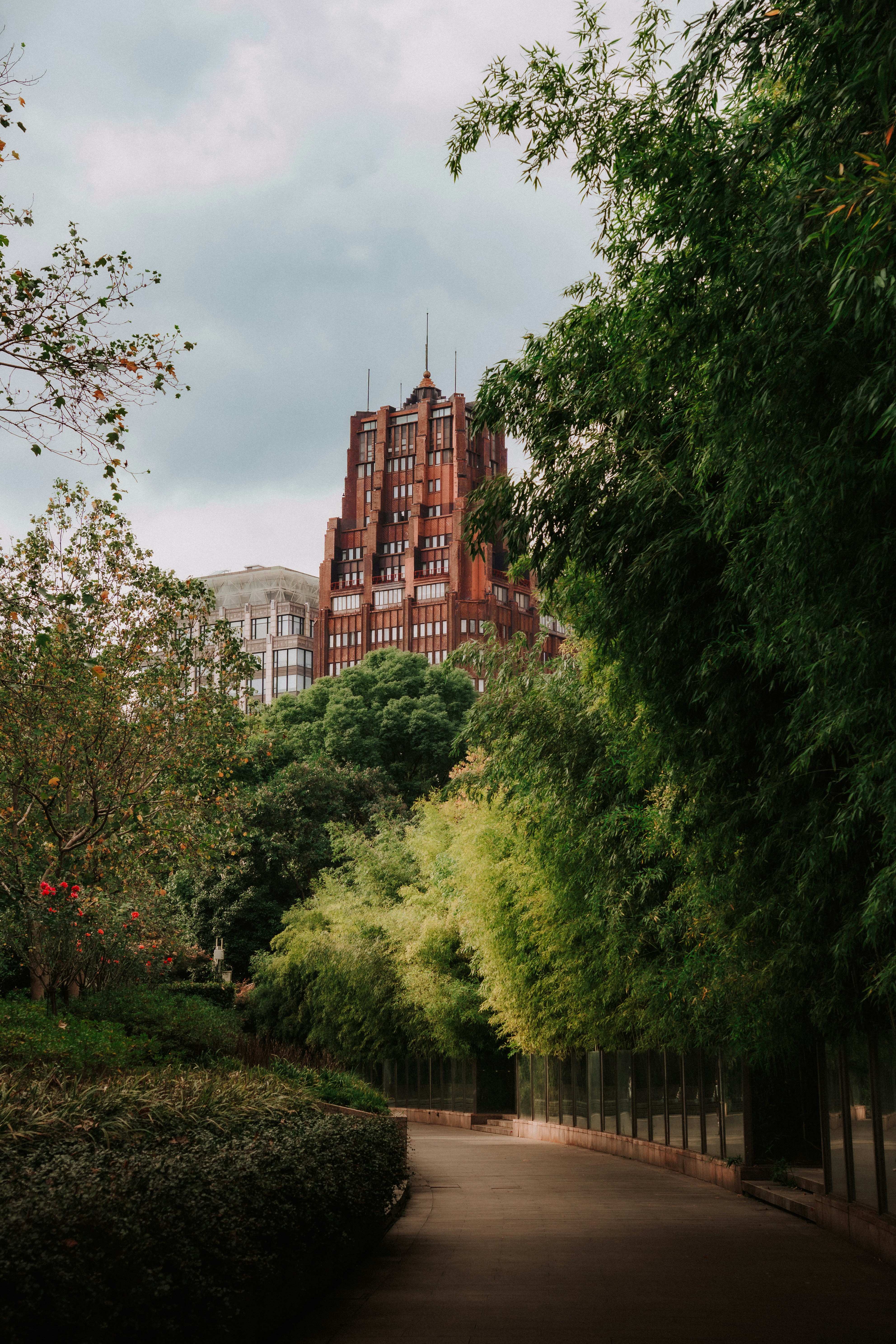 Brick Tower Emerges Through a Canopy of Trees Along a City Park Path