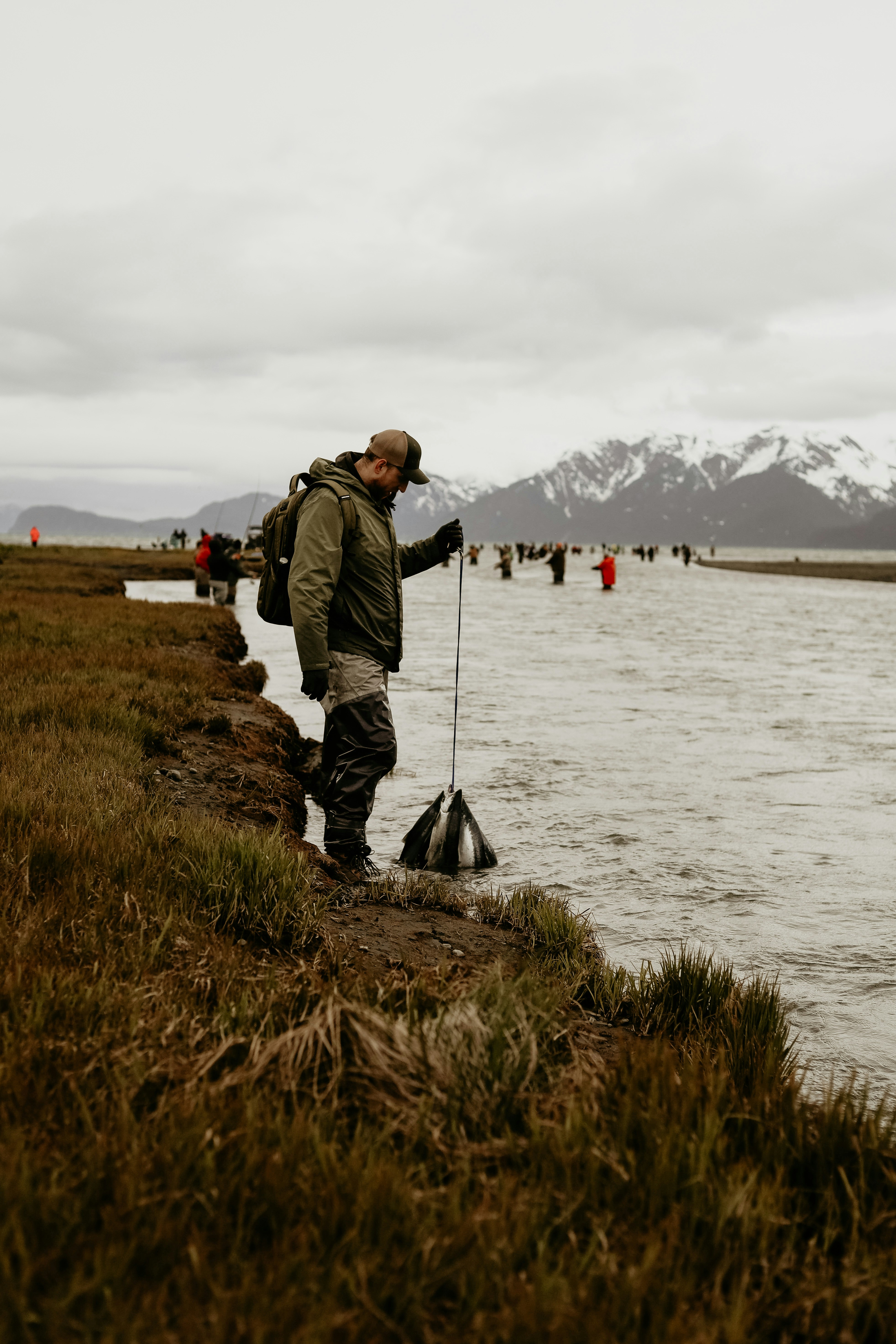 Riverside Resolve: Angler at the Verge of a Snow-Kissed Range