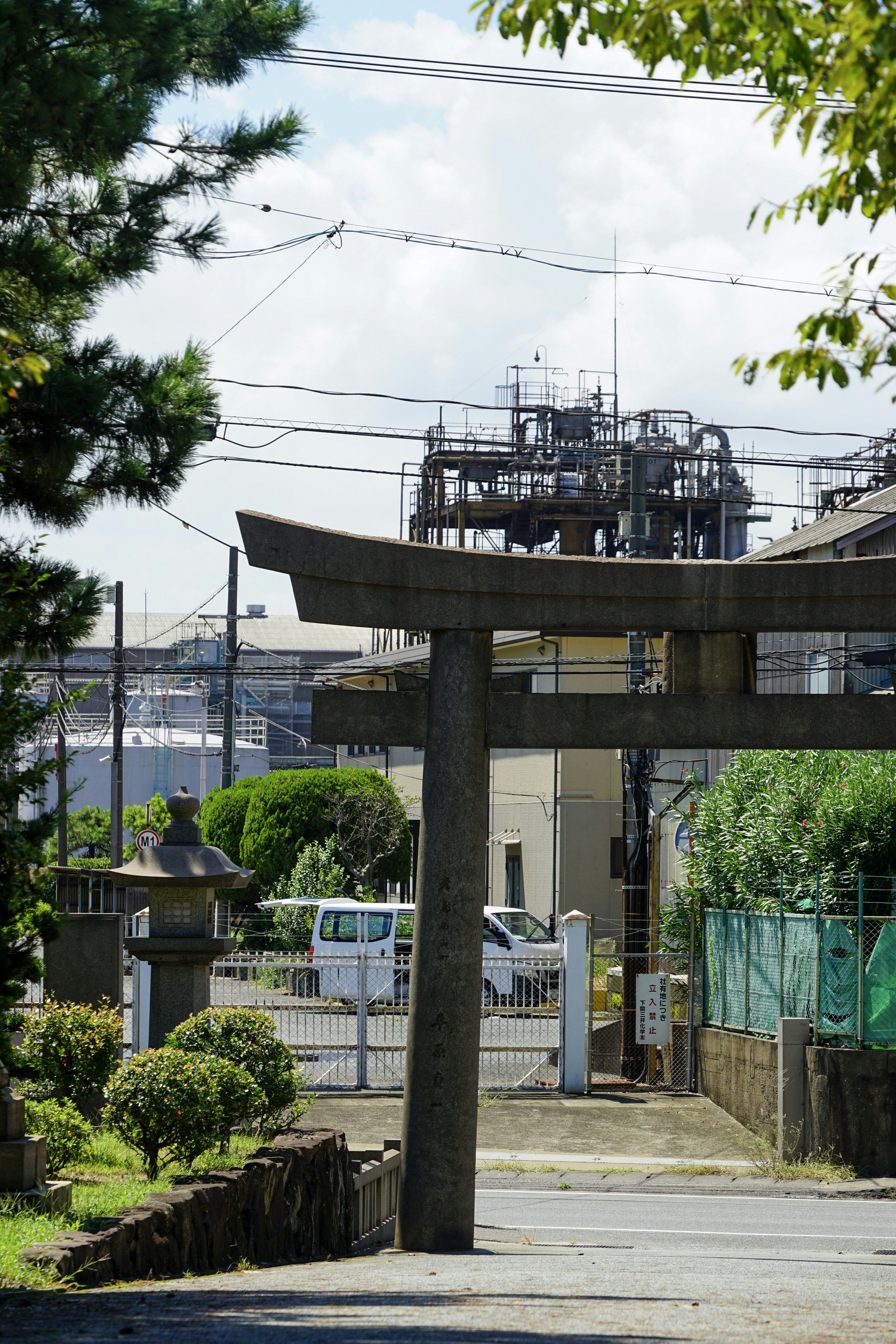 Torii Gate Framing a Quiet Shrine Path Against a Distant Industrial Horizon