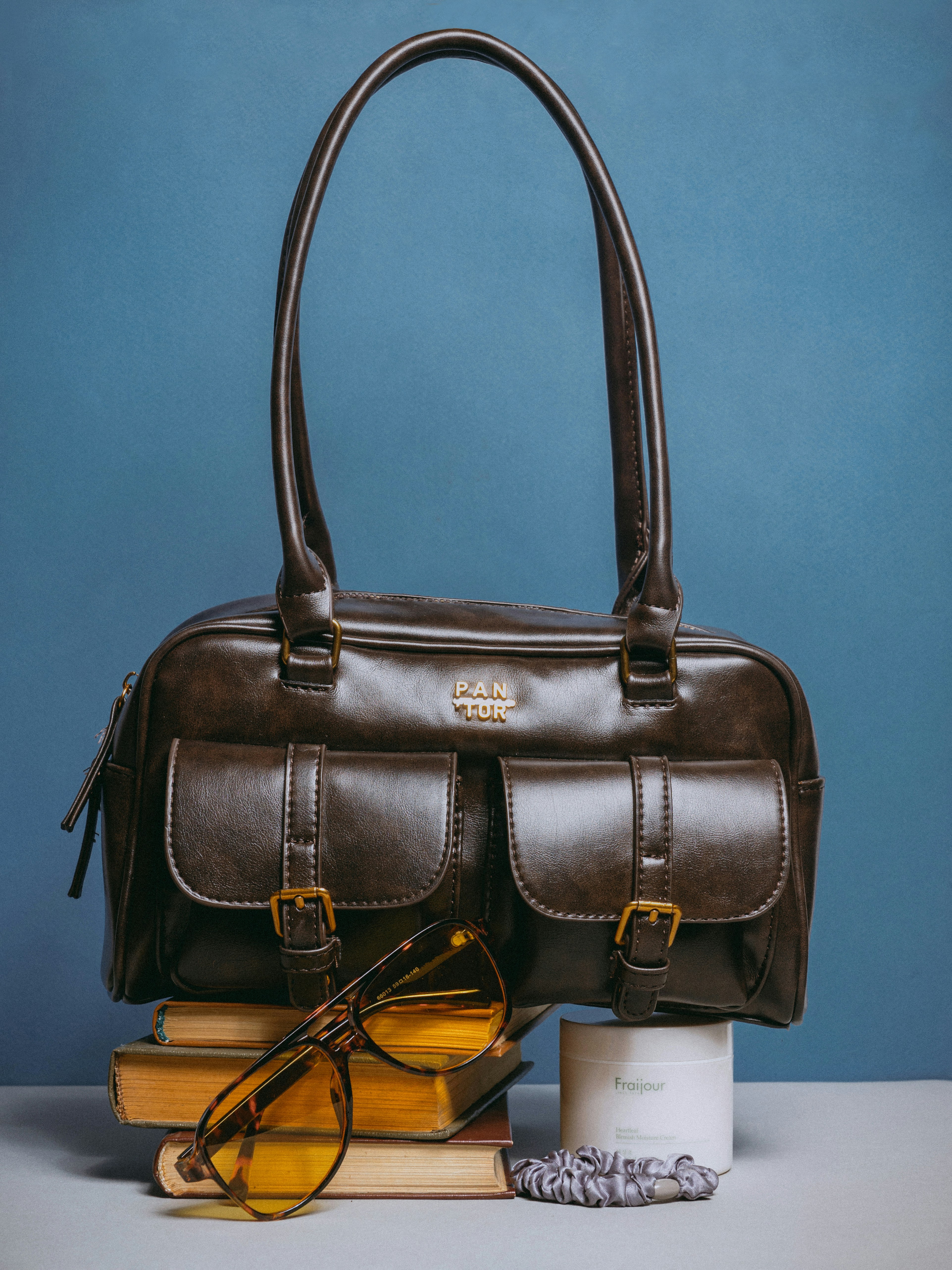A brown purse sitting on top of a stack of books photo – Free Bag Image ...