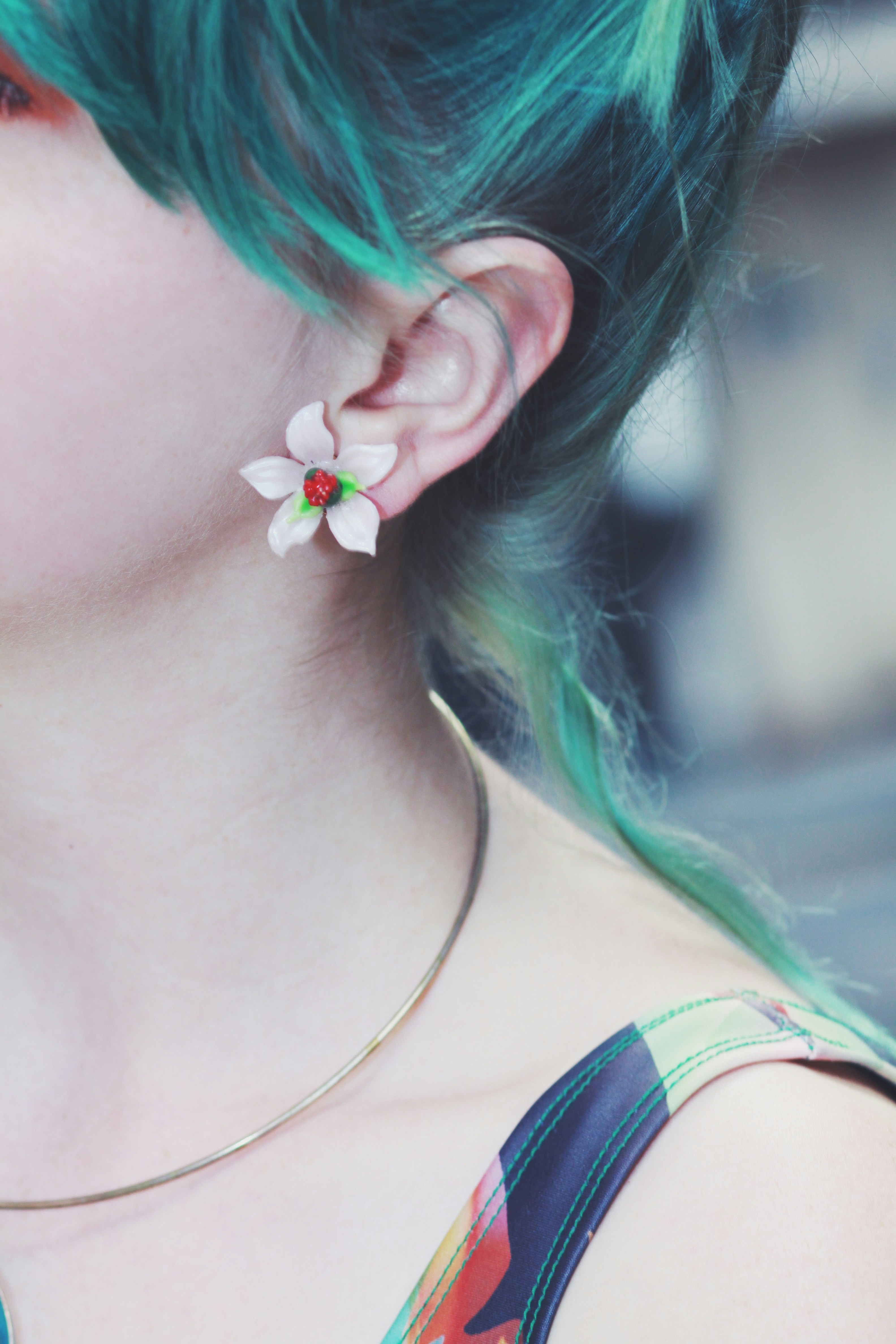 A woman with green hair and a flower in her ear