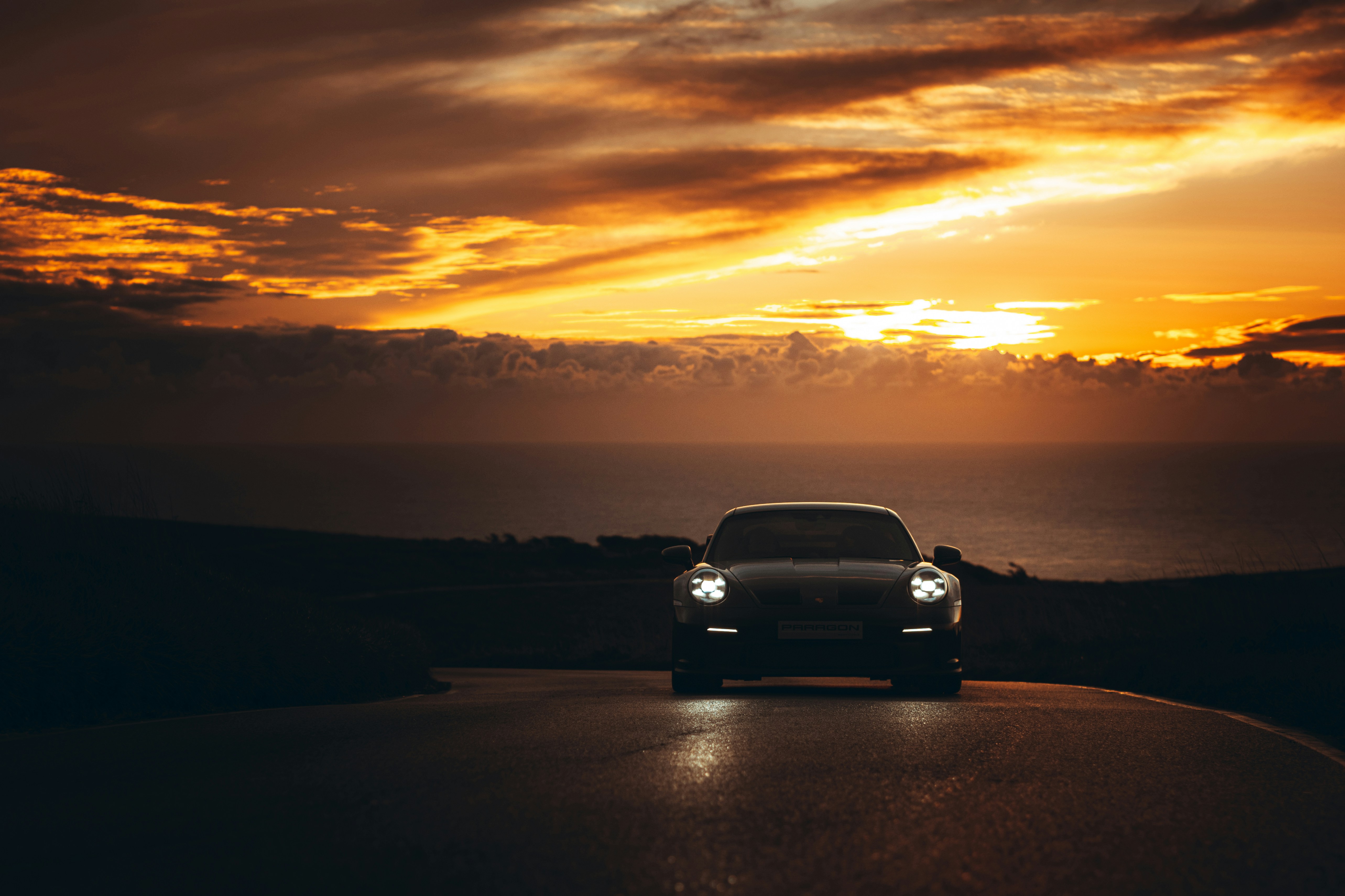 A car driving down a road with a sunset in the background photo – Free ...