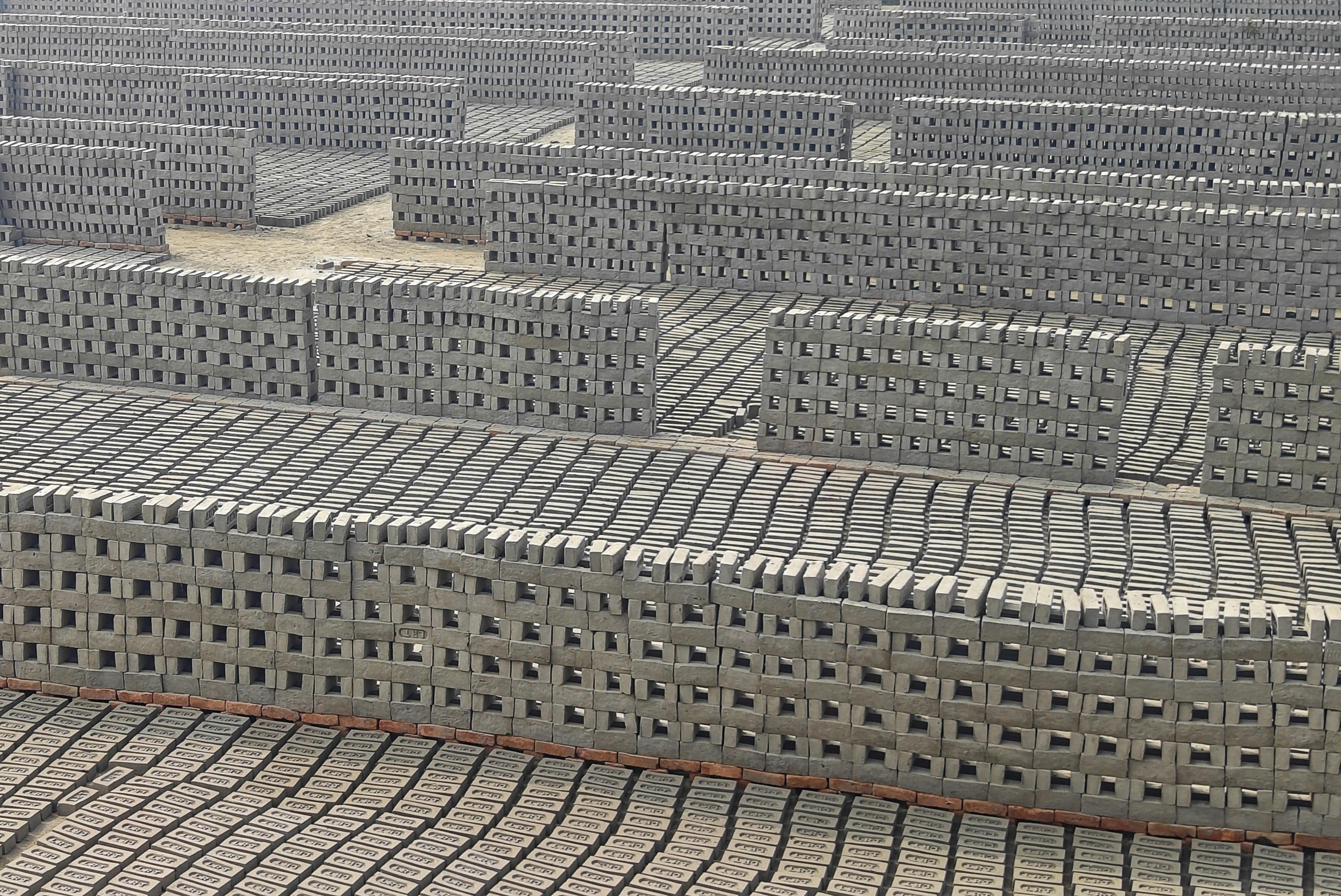 Perforated concrete blocks arranged in orderly, receding rows create a geometric field of texture and depth. The image emphasizes repetitive architecture and industrial material.