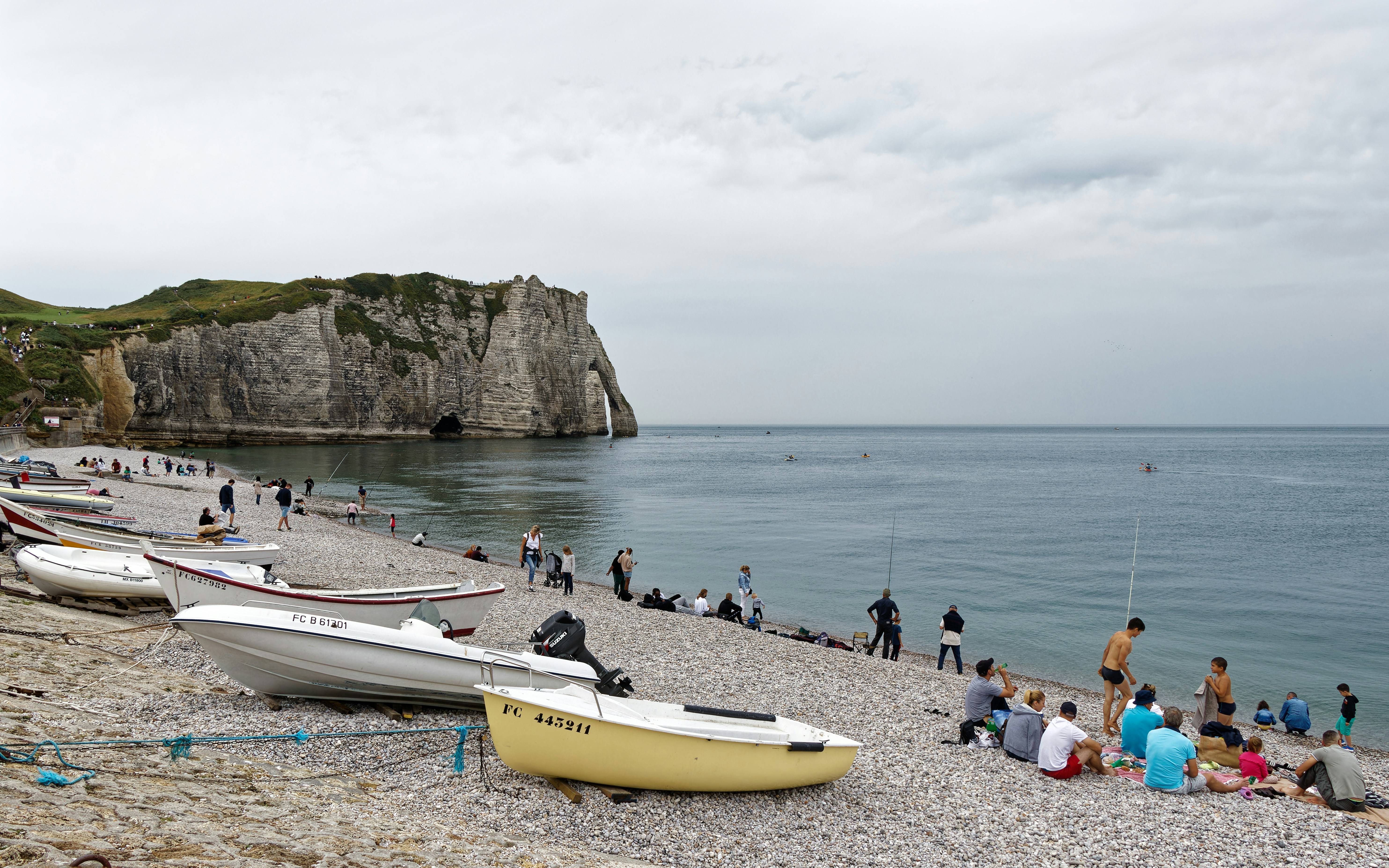 Cliffs, boats, and a pebbled shore under a calm horizon