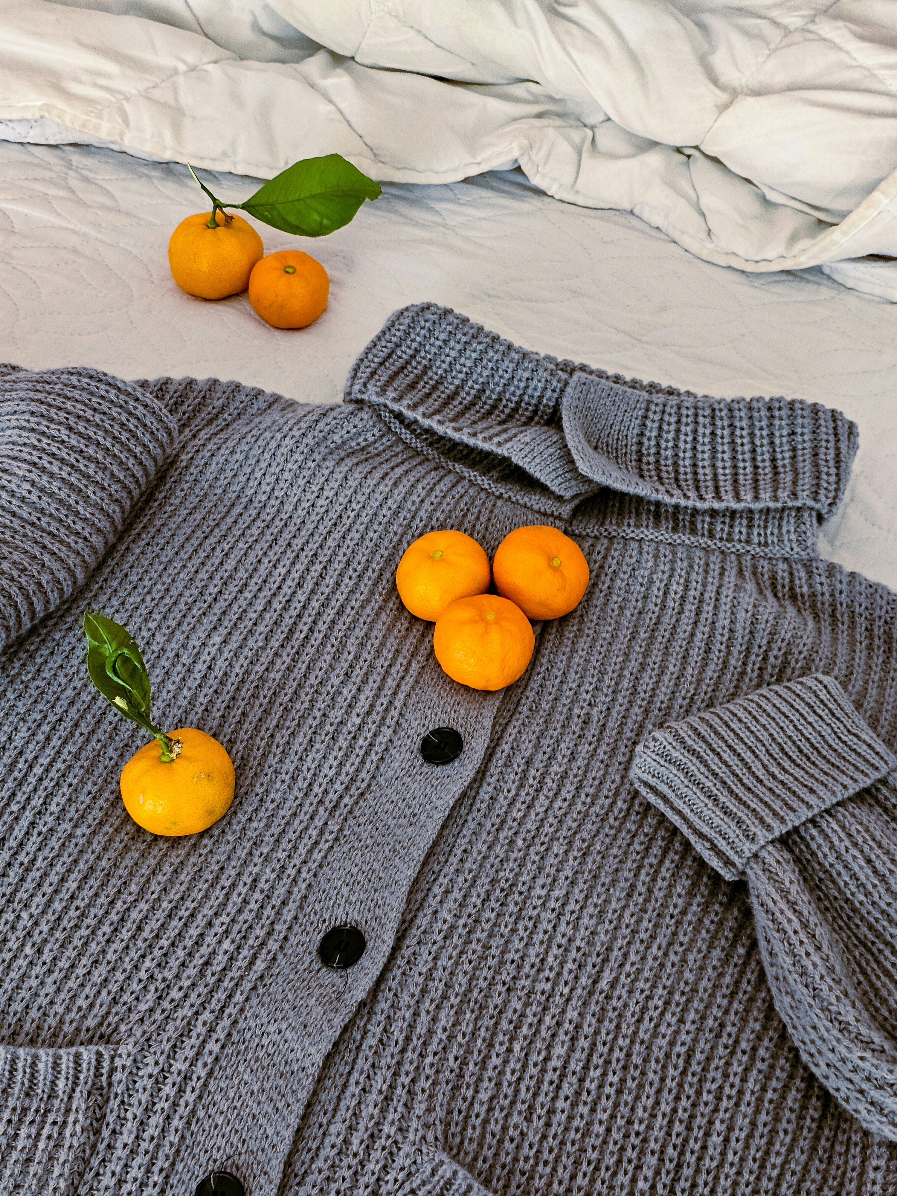 Three Oranges Nestled on a Gray Cable-Knit Cardigan: A Cozy Still-Life