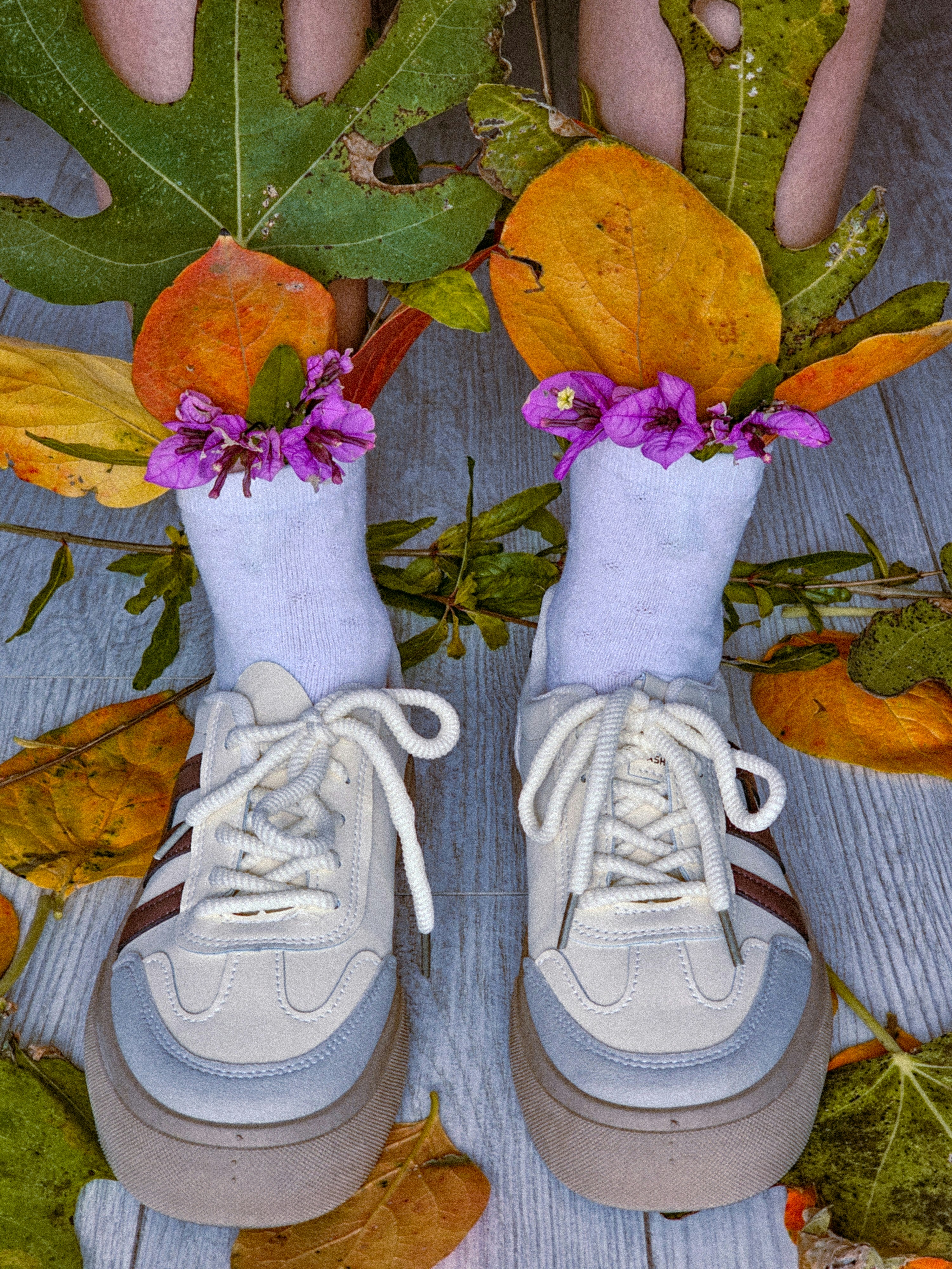 Autumn Steps: White Sneakers Grounded by Leaves and Bloom