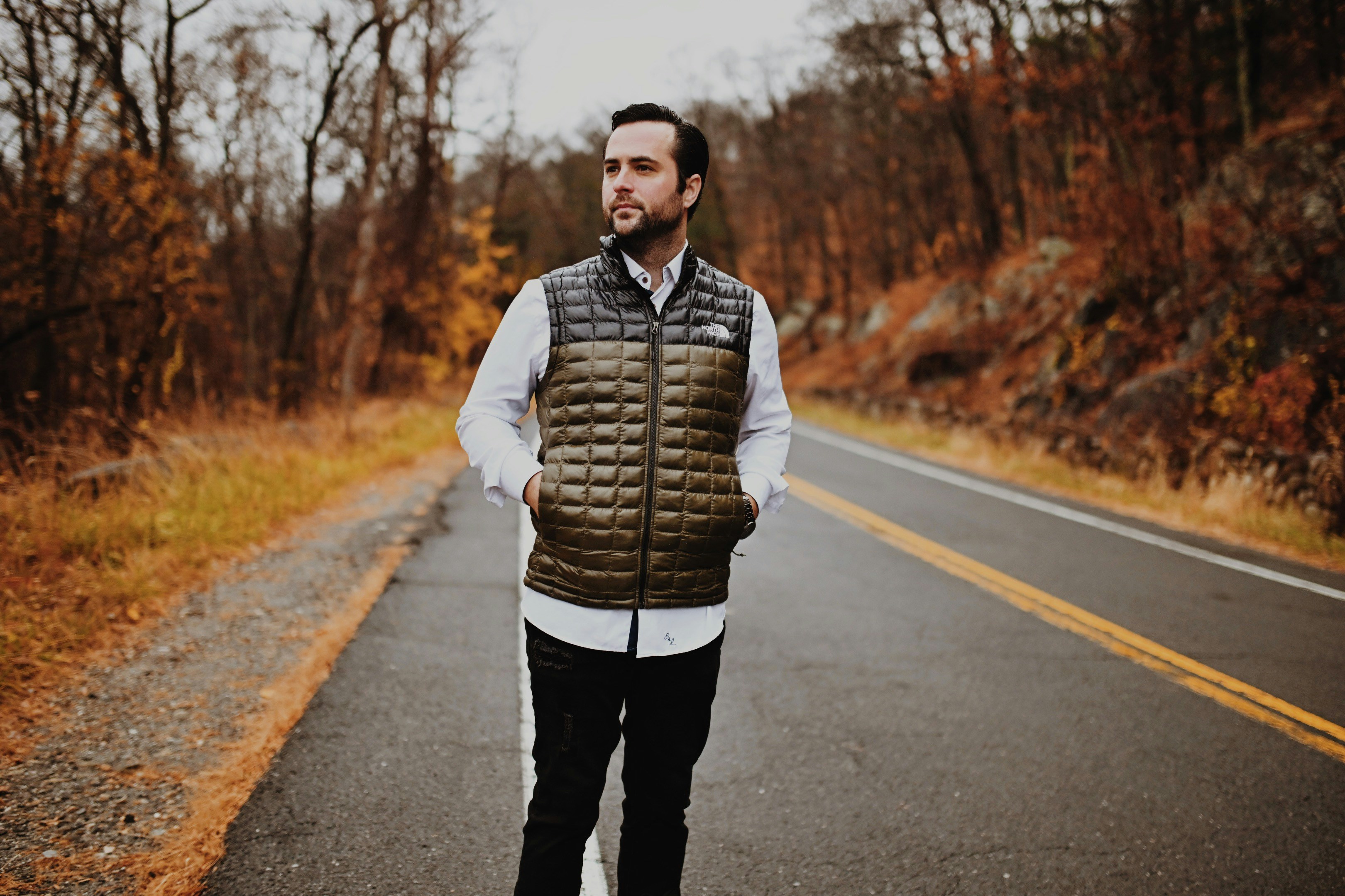 Autumn Road Portrait: Man in a Quilted Vest Amid Colorful Foliage